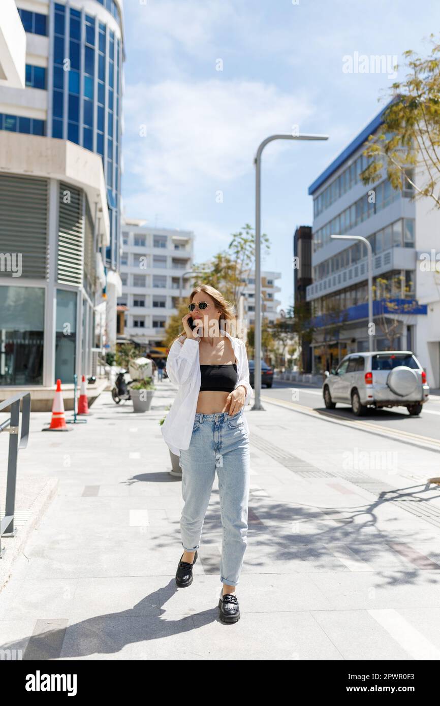 Image of beautiful stylish woman walking on city street on summer day ...