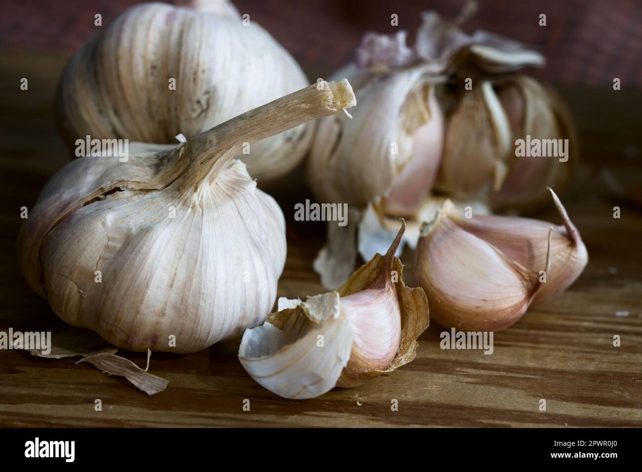 Detail of some purple garlic heads with some loose garlic on a wooden ...