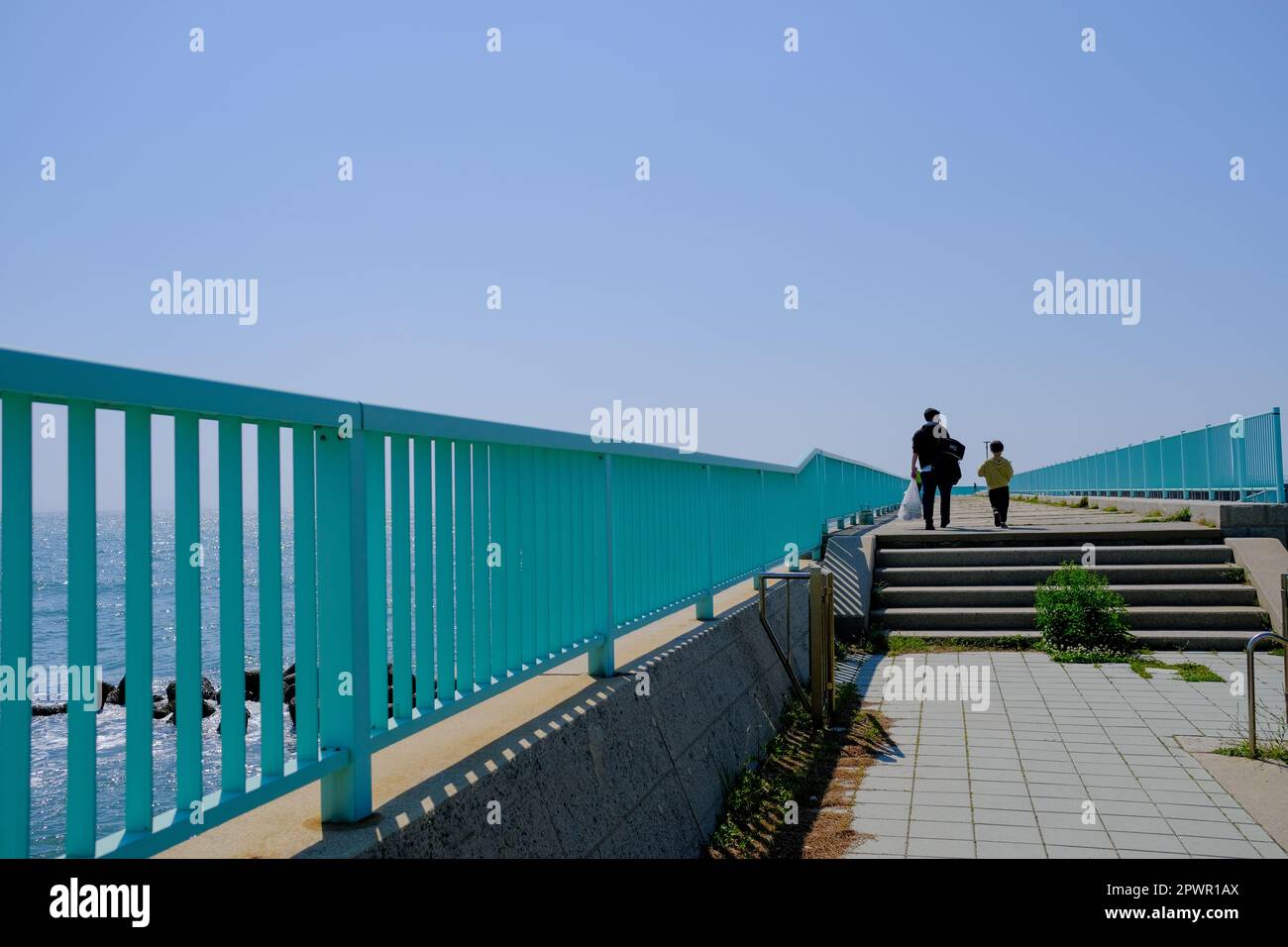 Father and son walking along the jetty at Fukuma Seaside Park, Fukuoka ...