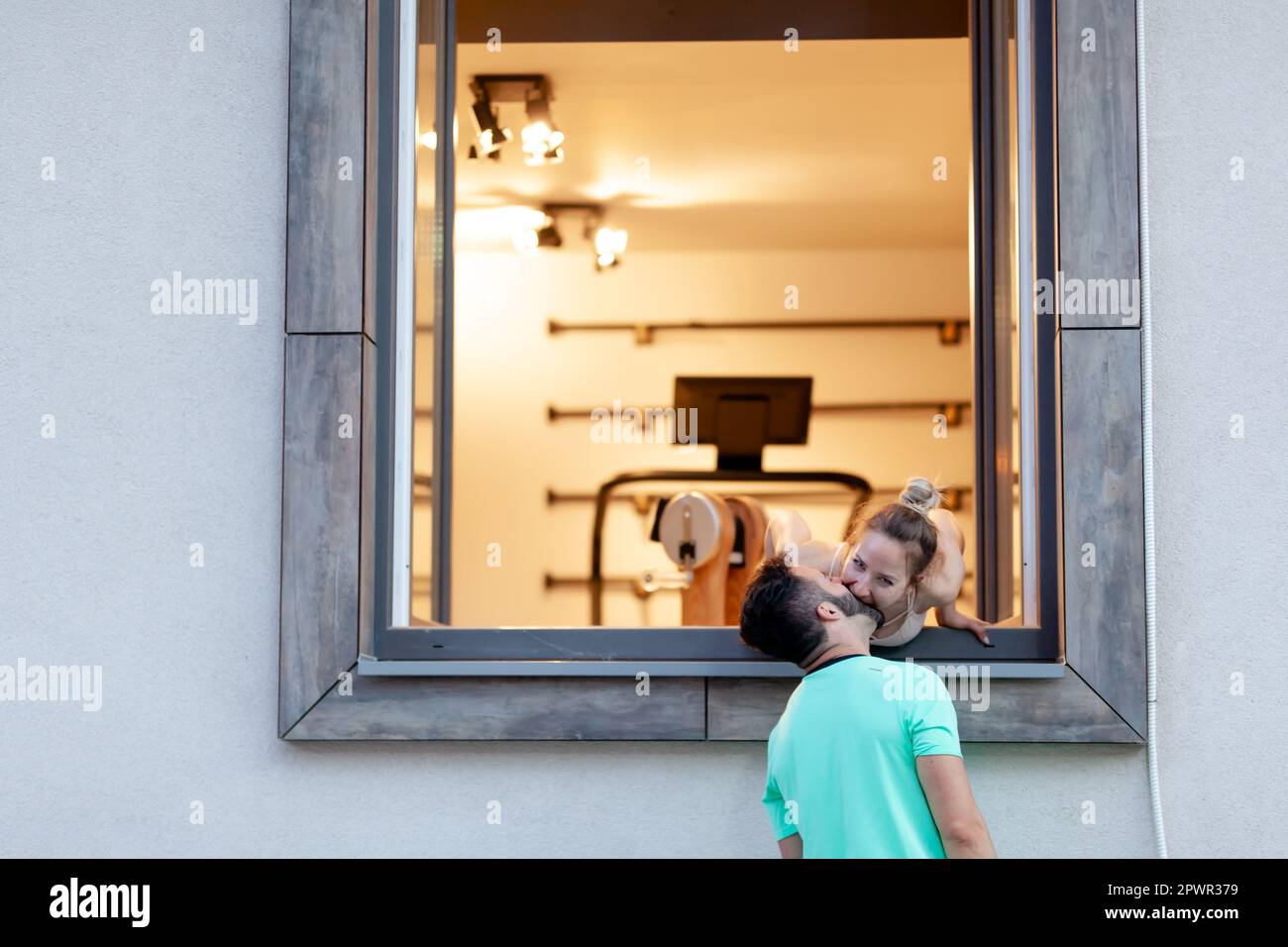 Couple in love. Boy standing outdoors kissing a girl from within a ...