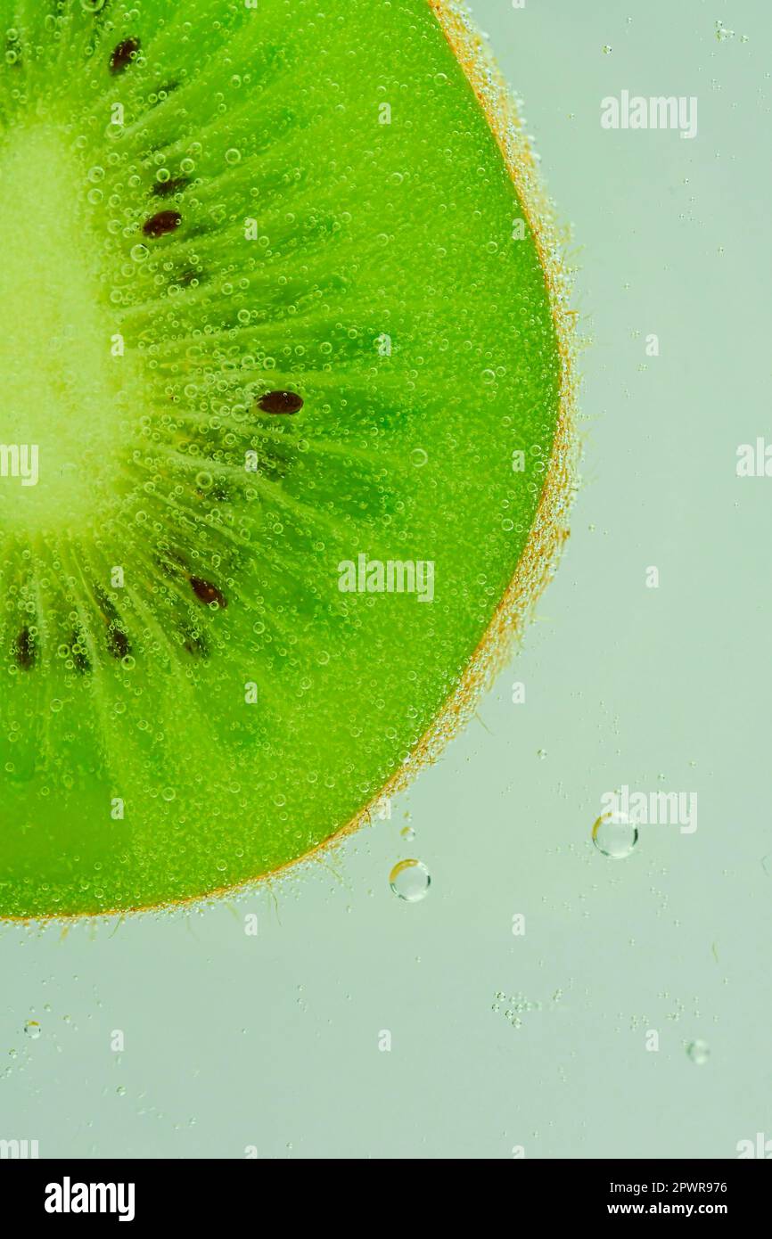 Fresh kiwi fruit slice in liquid with bubbles. Close-up of a kiwi fruit ...