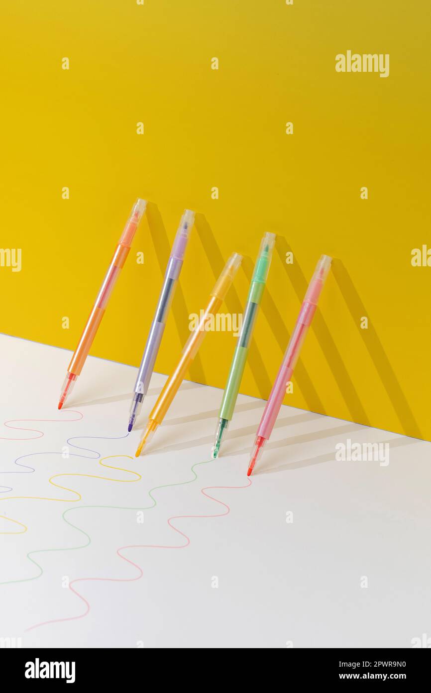 Colored markers stand against a yellow background. Art concept ...