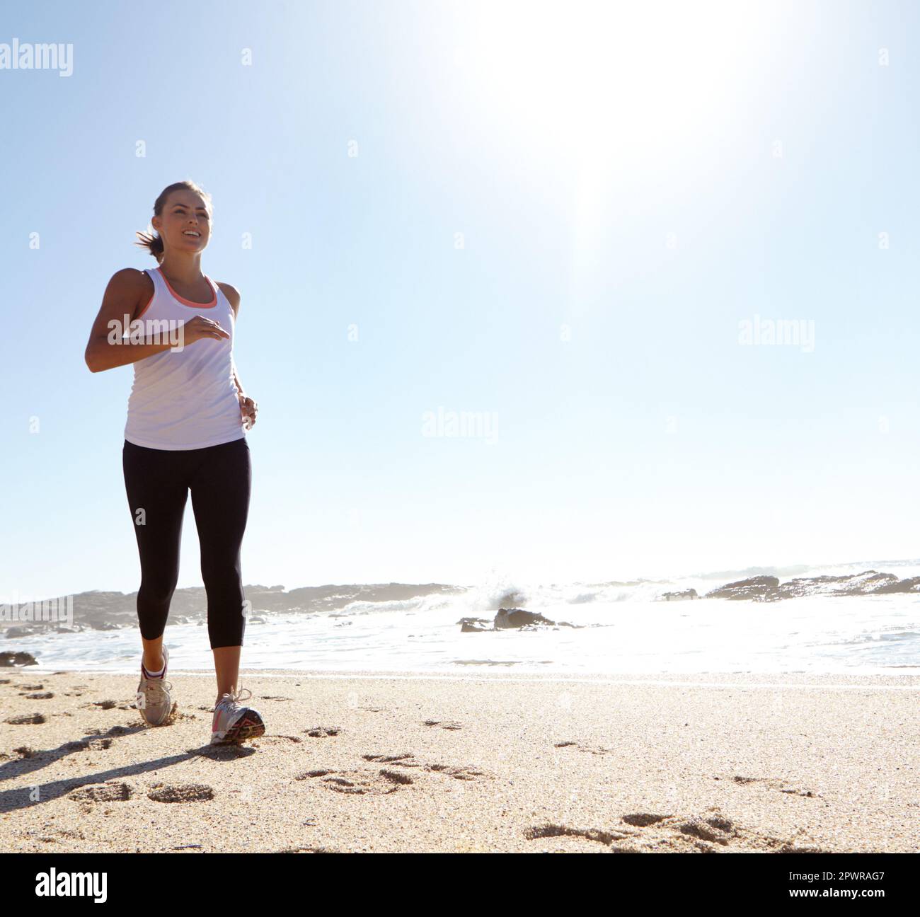 Going for a run in the sun. a young woman jogging on the beach Stock ...