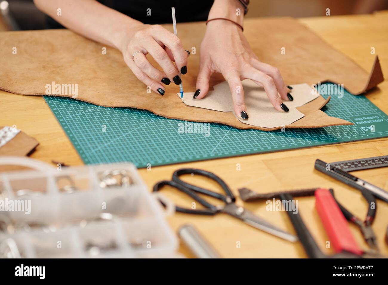 Closeup image of woman tracing pattern on leather piece Stock Photo - Alamy