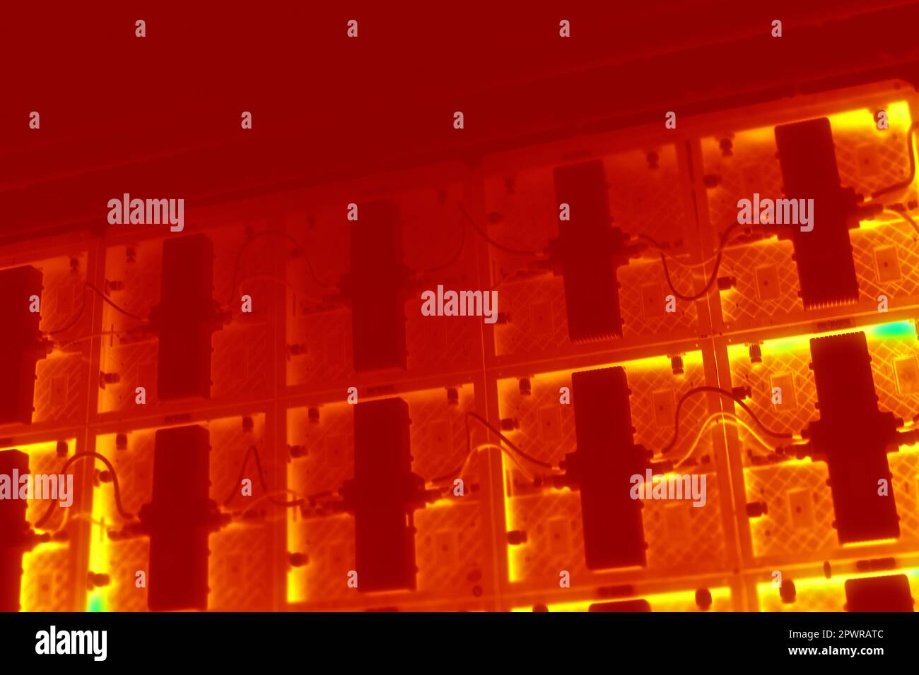 A modern device radiates a vibrant red and yellow heat from its panels ...