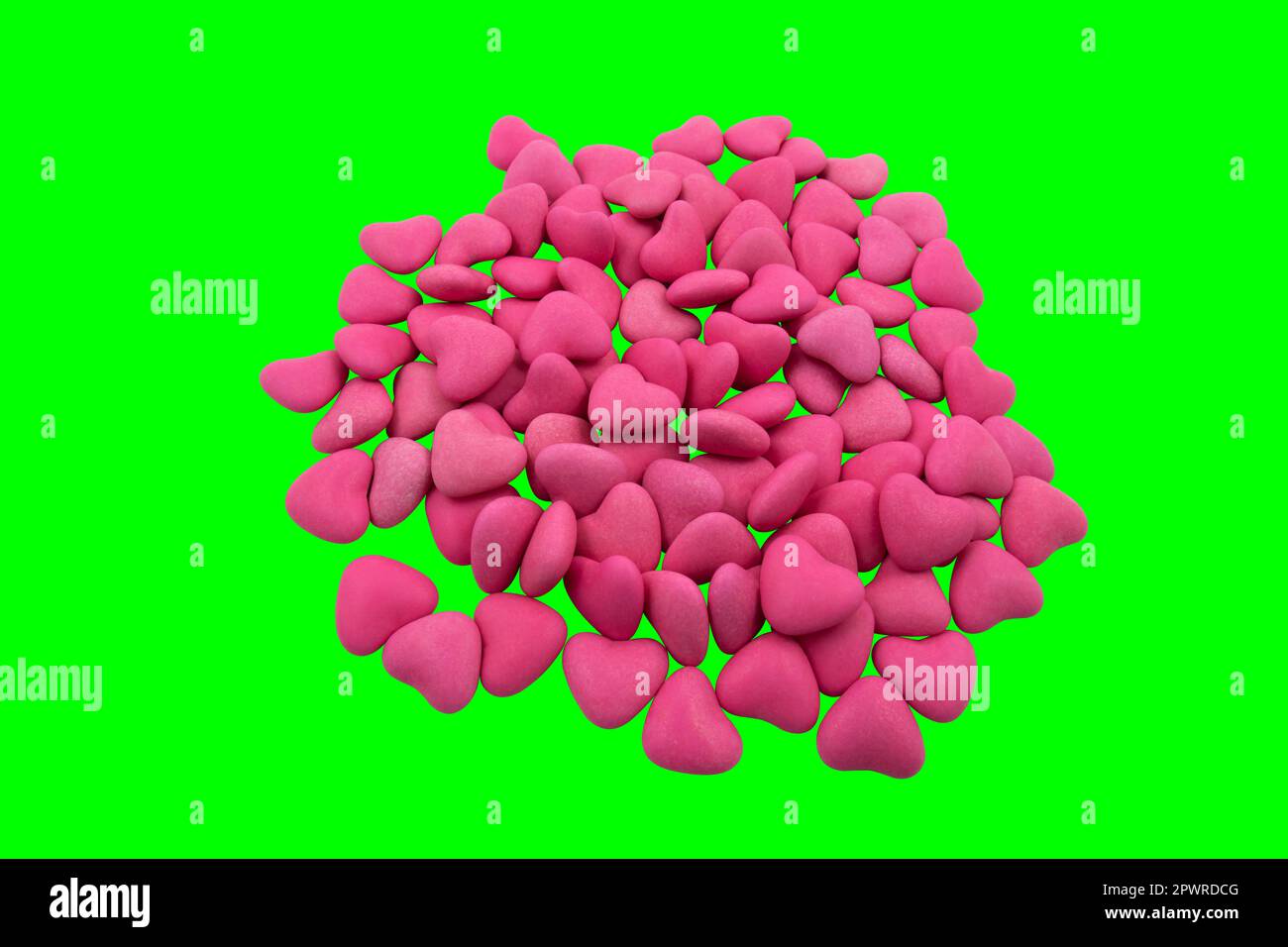A bunch of pink candies in the shape of hearts (close-up), on a green ...