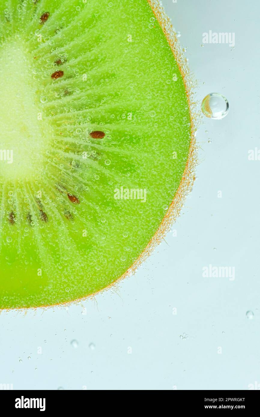 Fresh kiwi fruit slice in liquid with bubbles. Close-up of a kiwi fruit ...