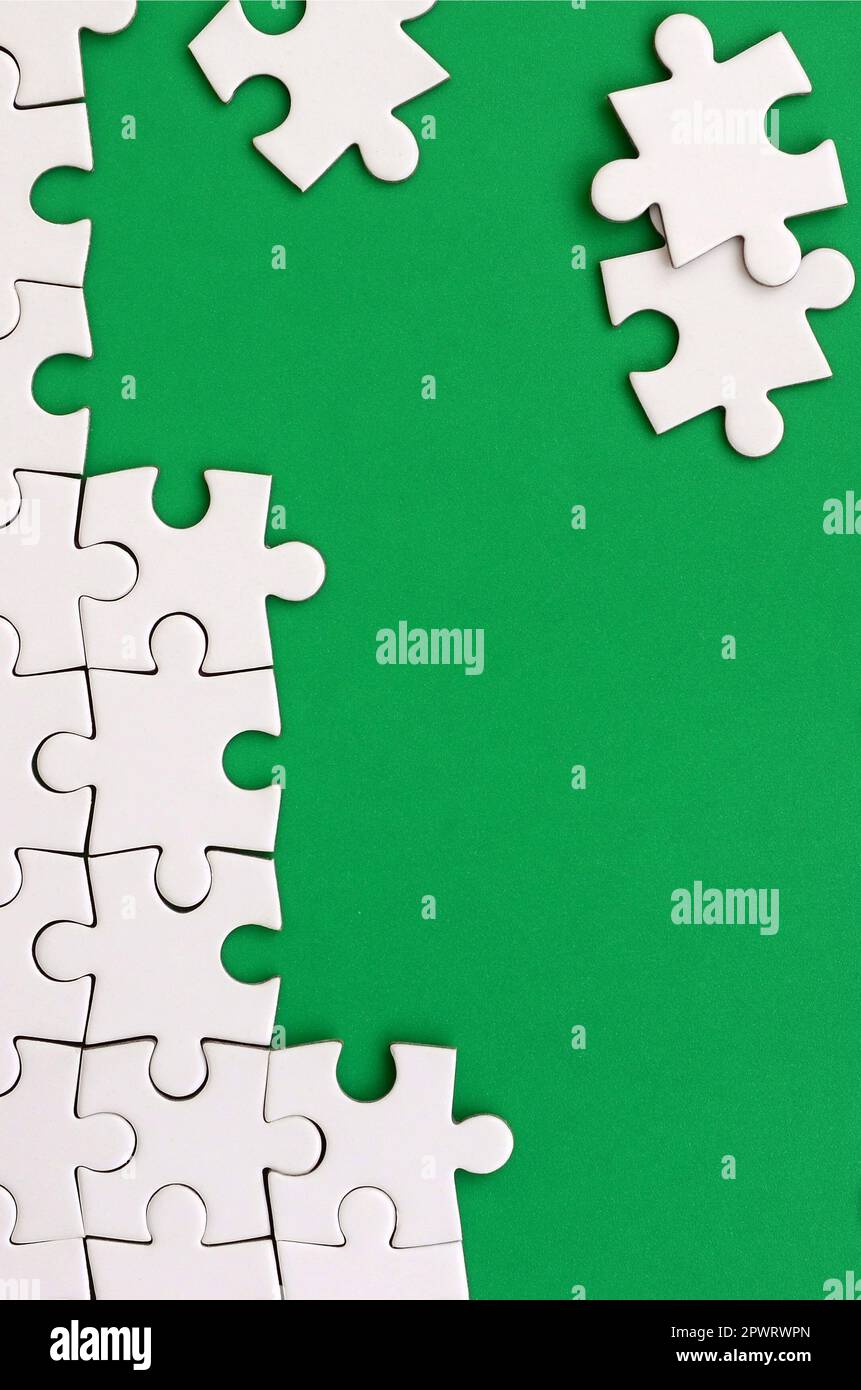 Fragment of a folded white jigsaw puzzle and a pile of uncombed puzzle ...