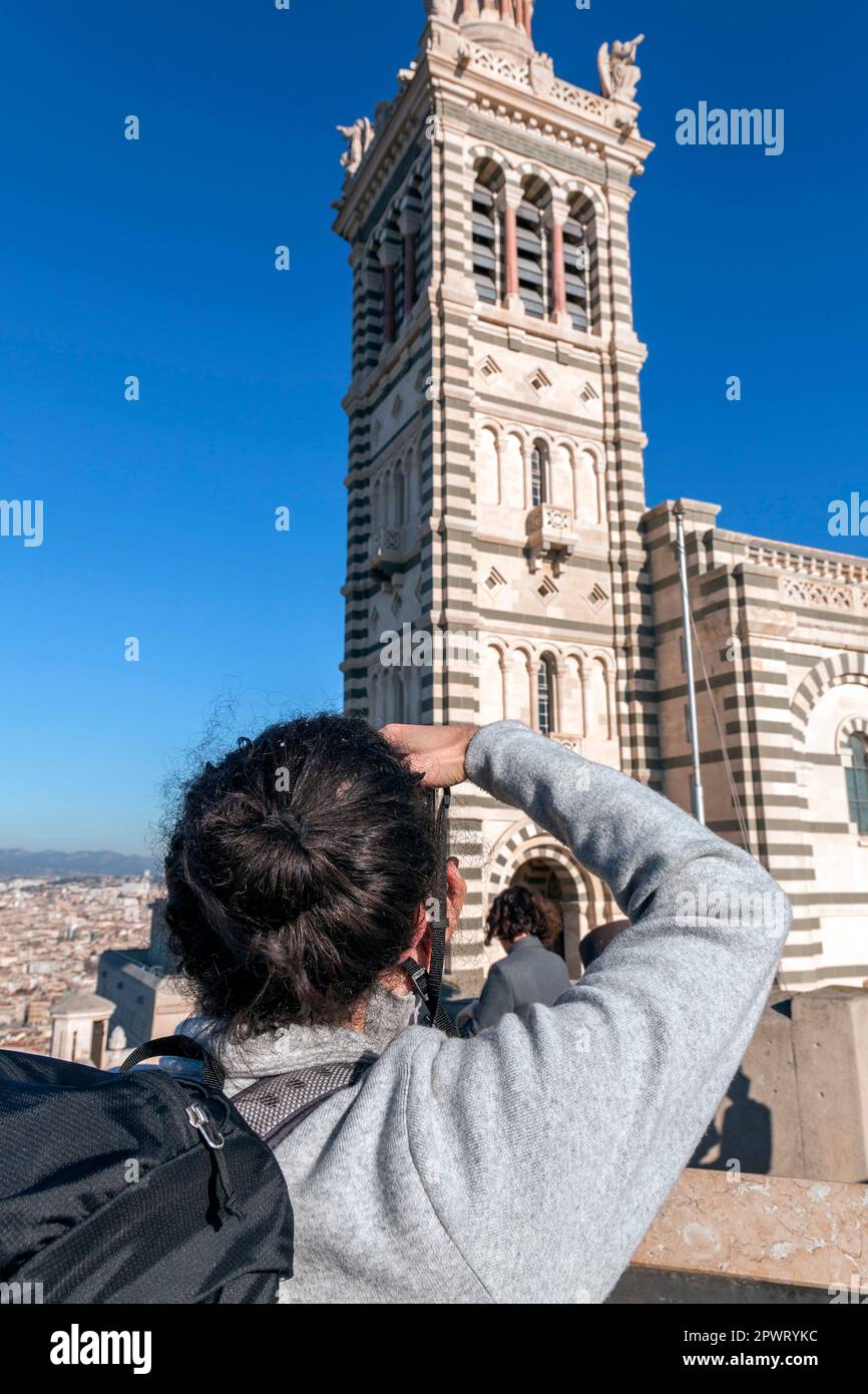 Young male visitor taking photos of the Notre-Dame de la Garde basilica ...