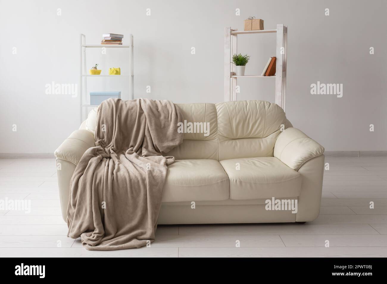 Beige sofa against white empty wall in simple living room interior ...