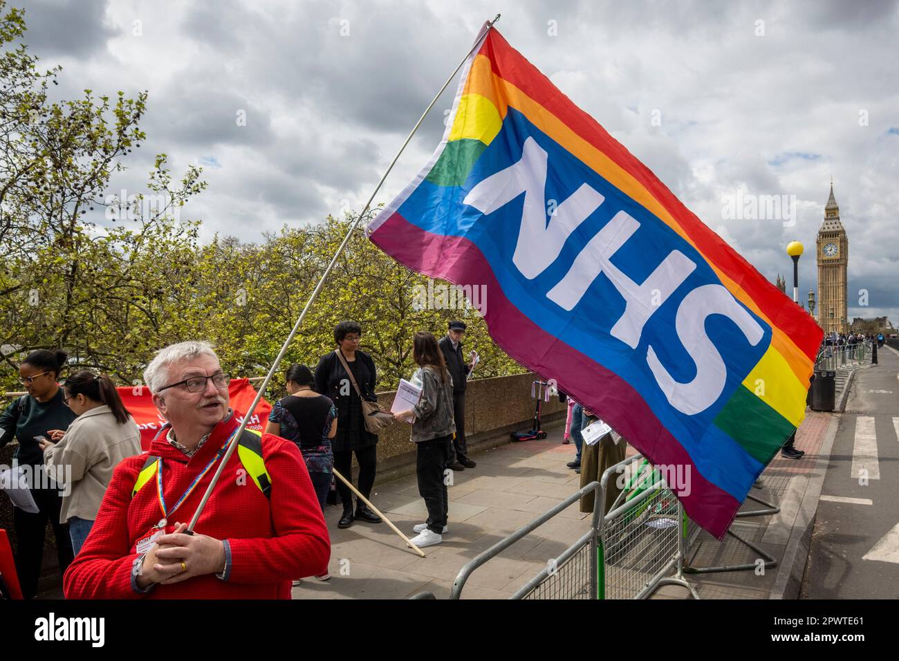 London, UK. 1 May 2023. An NHS worker with a large NHS flags at a pay ...