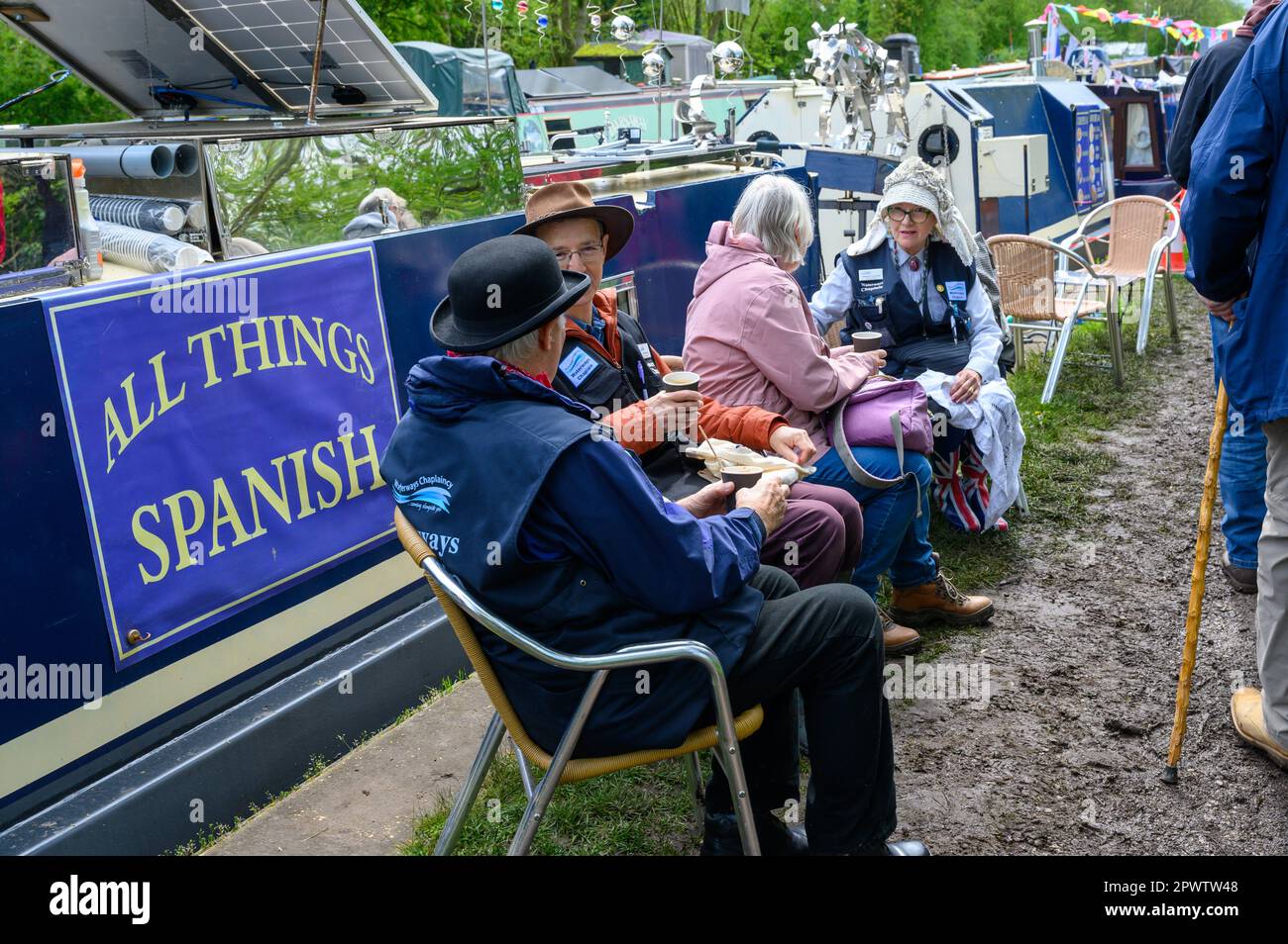 Group of people, some in period costume, sitting on a muddy canal ...