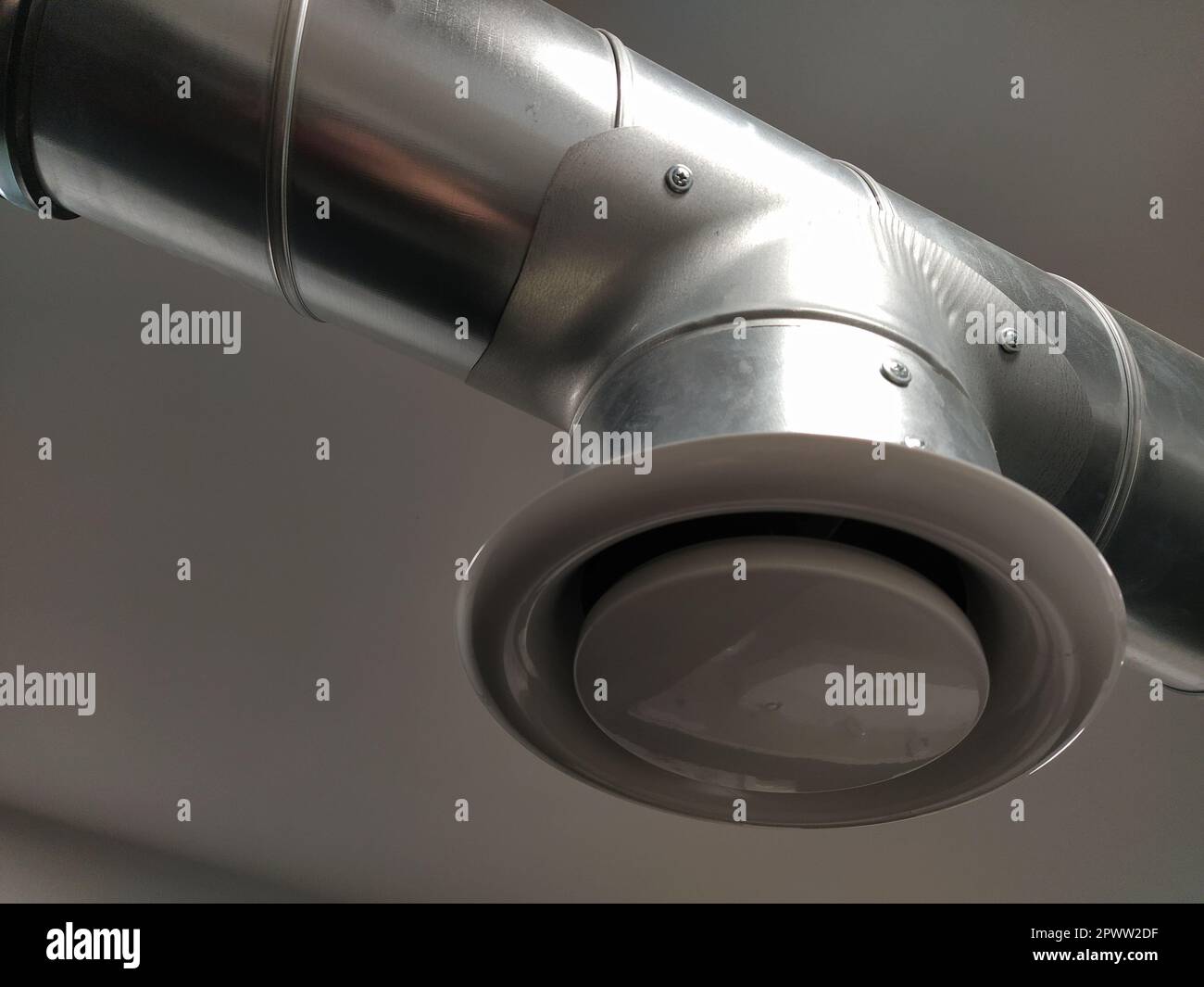 Extractor hood in a public toilet. Round metal pipe with gray air ...