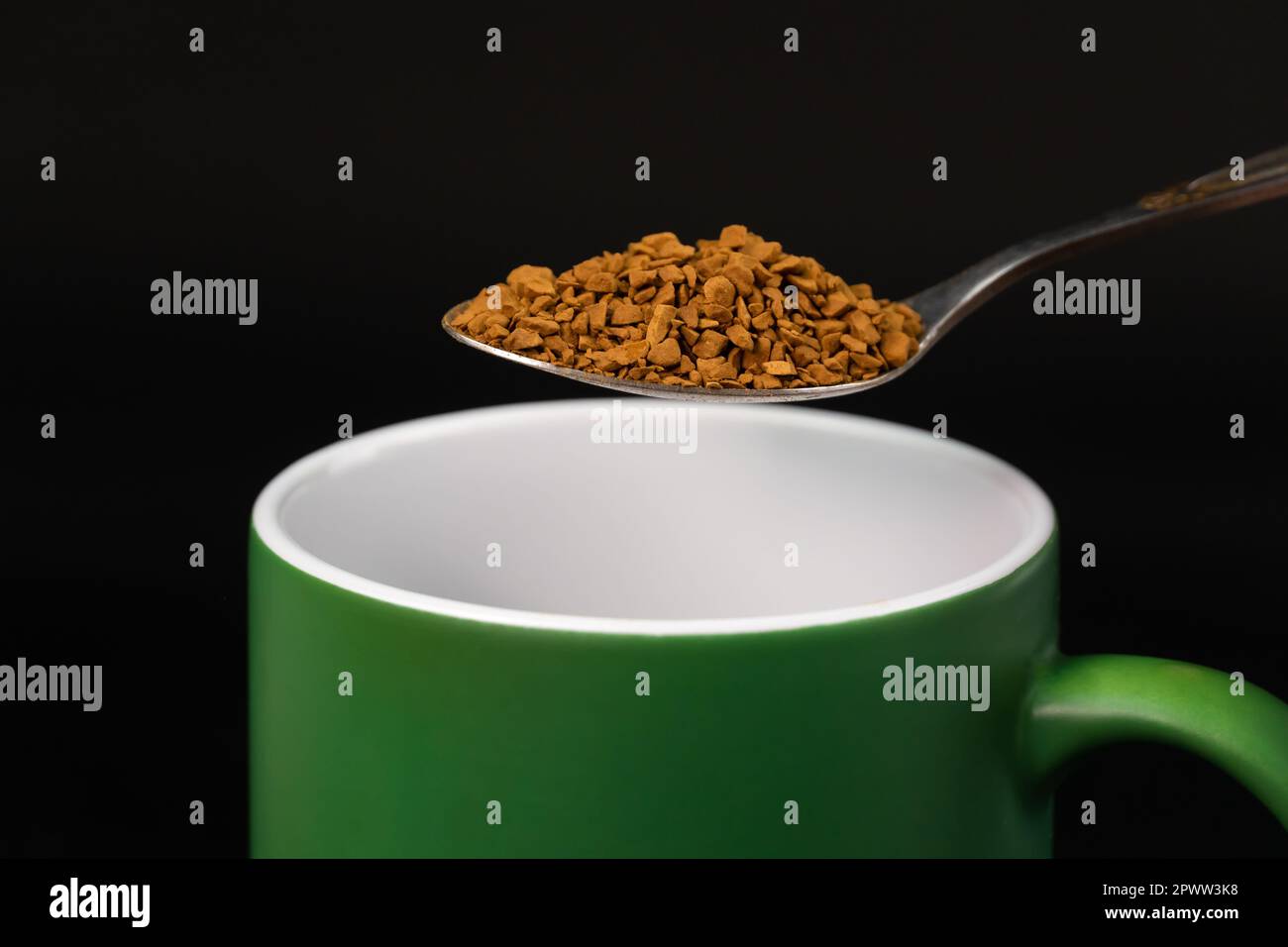 Close-up of a teaspoon with granulated instant coffee over a mug, macro ...