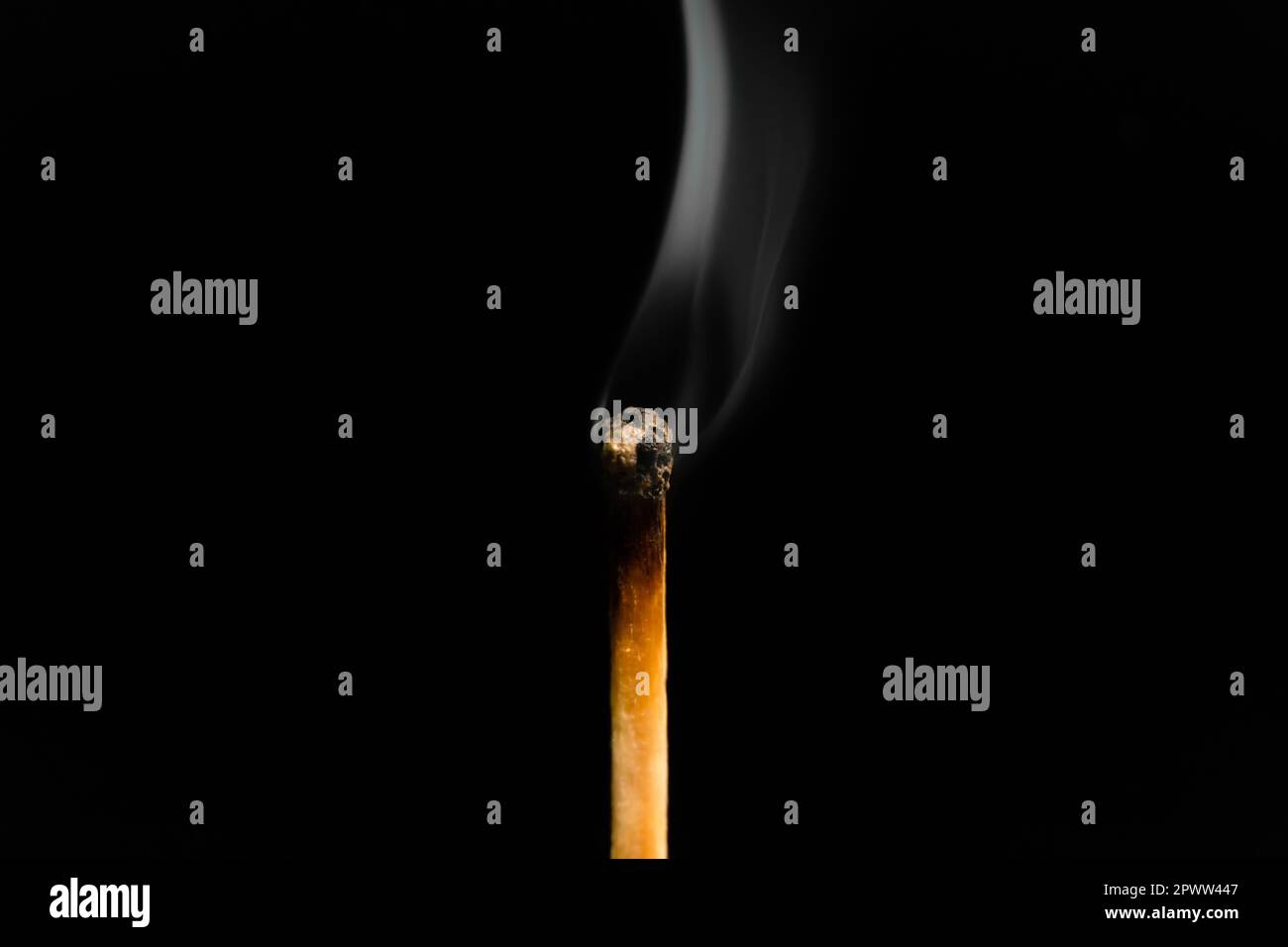A lit match with smoke on a black background, macro photography. An ...