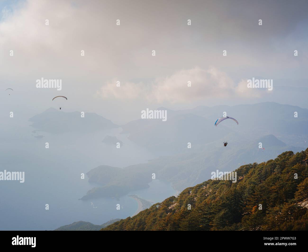 Paragliding in sky. Paraglider tandem flying over sea and mountains in ...