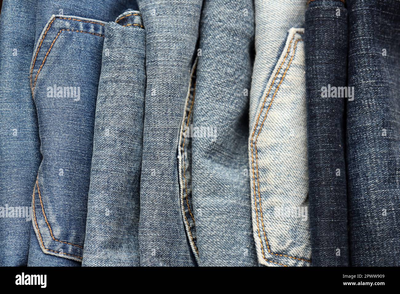 Many jeans in stack in wardrobe room. Row of pants denim jeans in ...