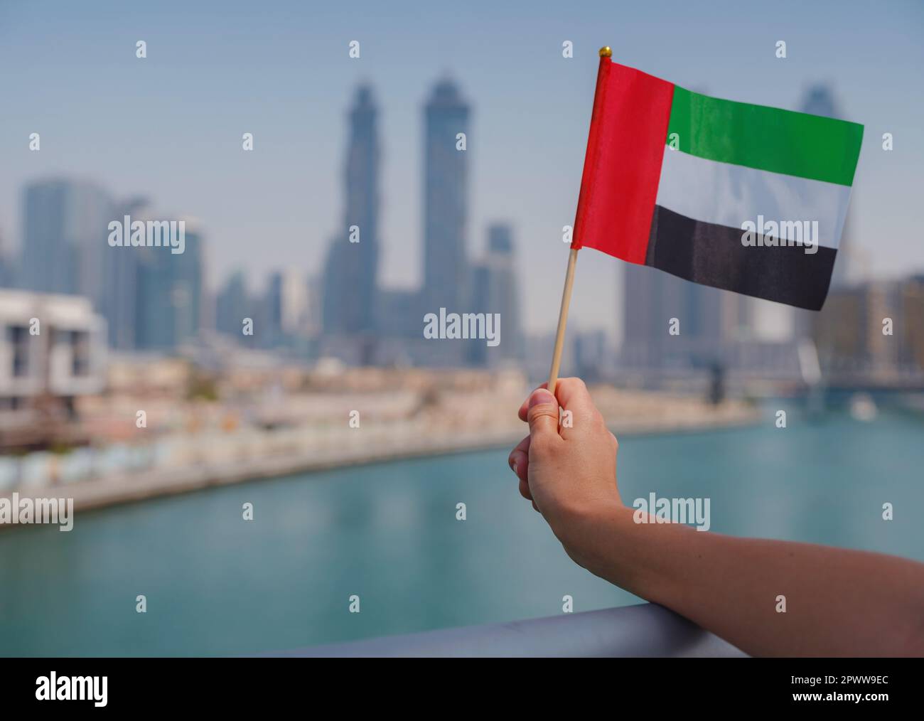 Close up of a female hand holding tiny flag of UAE against Dubai ...