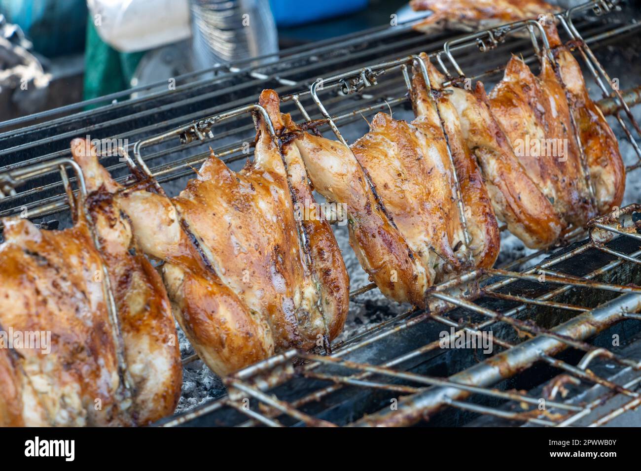 A row of chickens are grilled on a rotating grate, street restaurant ...