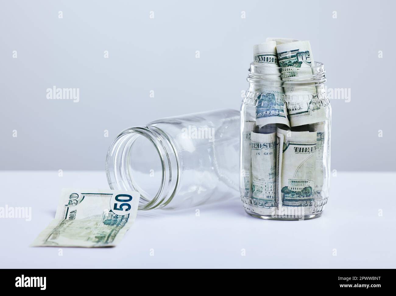 Lets start saving. two jars with bank notes against a grey background ...