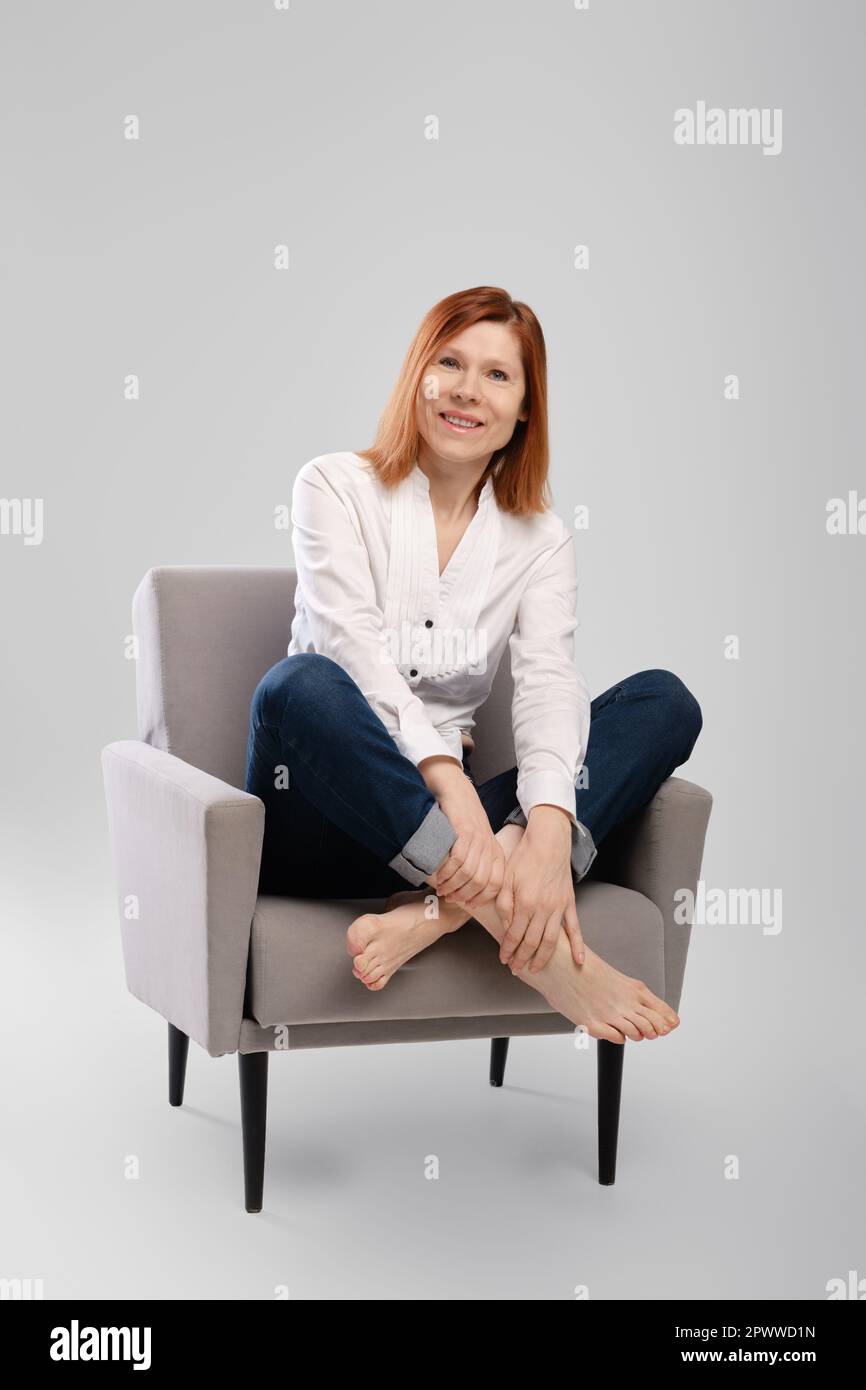 Barefoot middle age woman relax in cozy armchair. Studio concept of ...