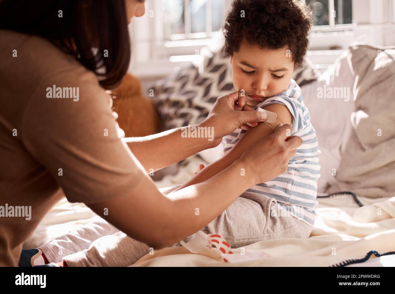 All soldiers have scars. a woman putting a plaster on her sons arm at ...