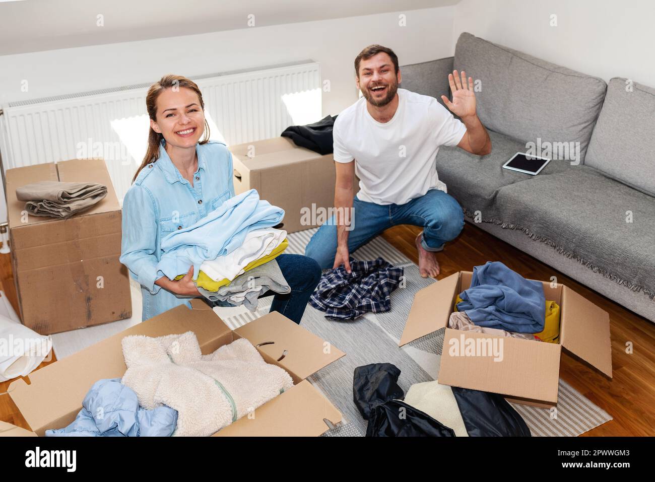 Happy young couple packing their clothes for donation, charitable ...