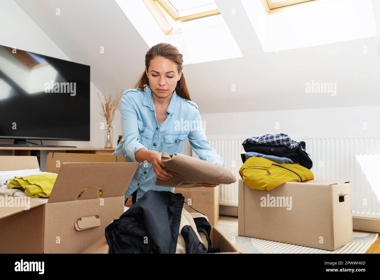 Woman unboxing her clothing, relocation concept Stock Photo - Alamy