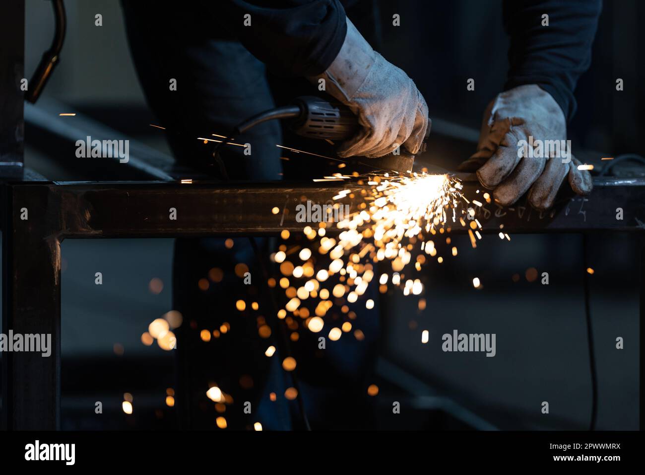 Man working on iron with grinder. Man at work. Sparkles and fire from ...