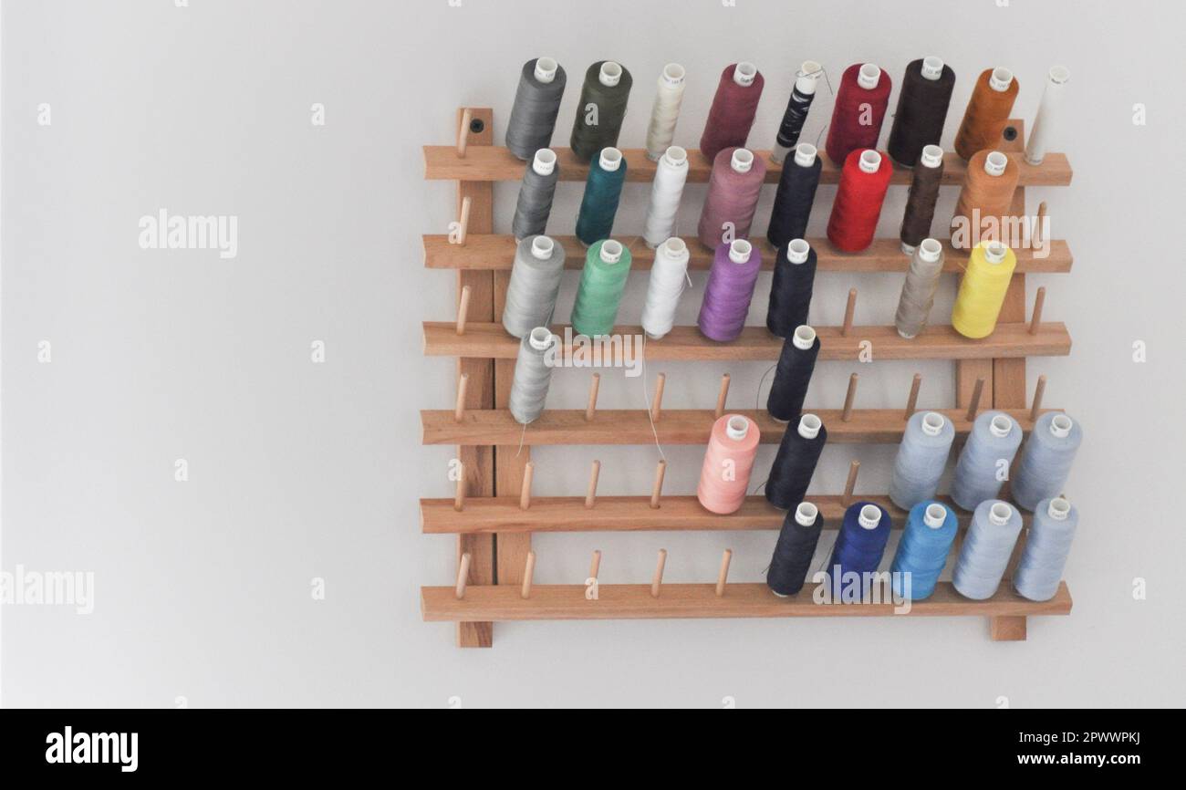 A collection of multi coloured sewing threads displayed on a wooden ...