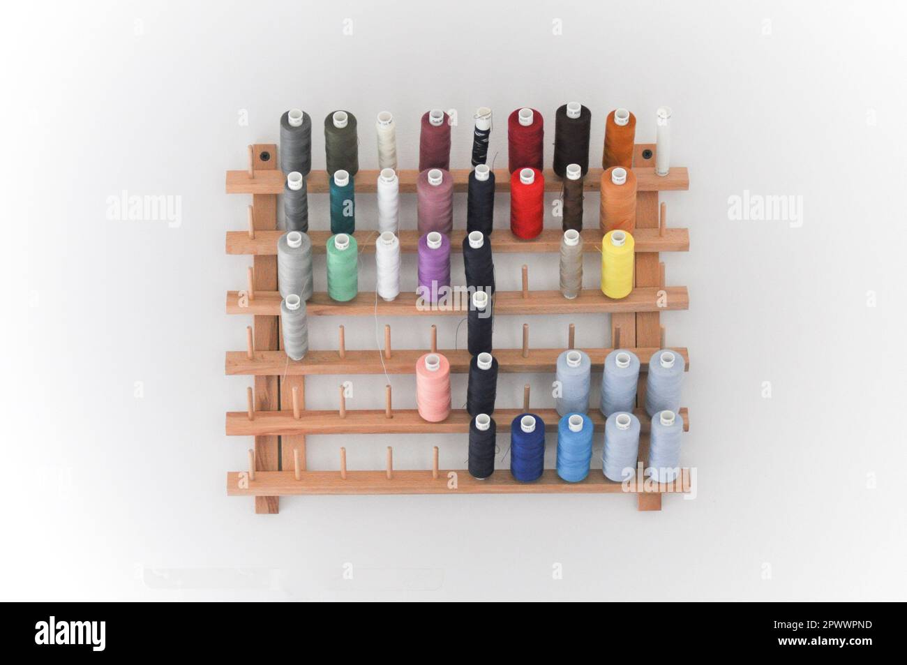 A collection of multi coloured sewing threads displayed on a wooden ...