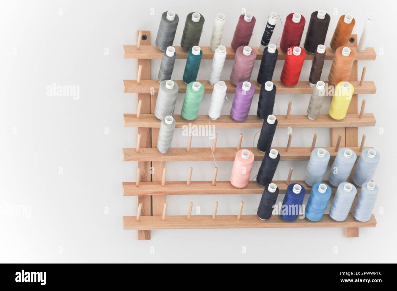 A collection of multi coloured sewing threads displayed on a wooden ... A collection of multi coloured sewing threads displayed on a wooden ...
