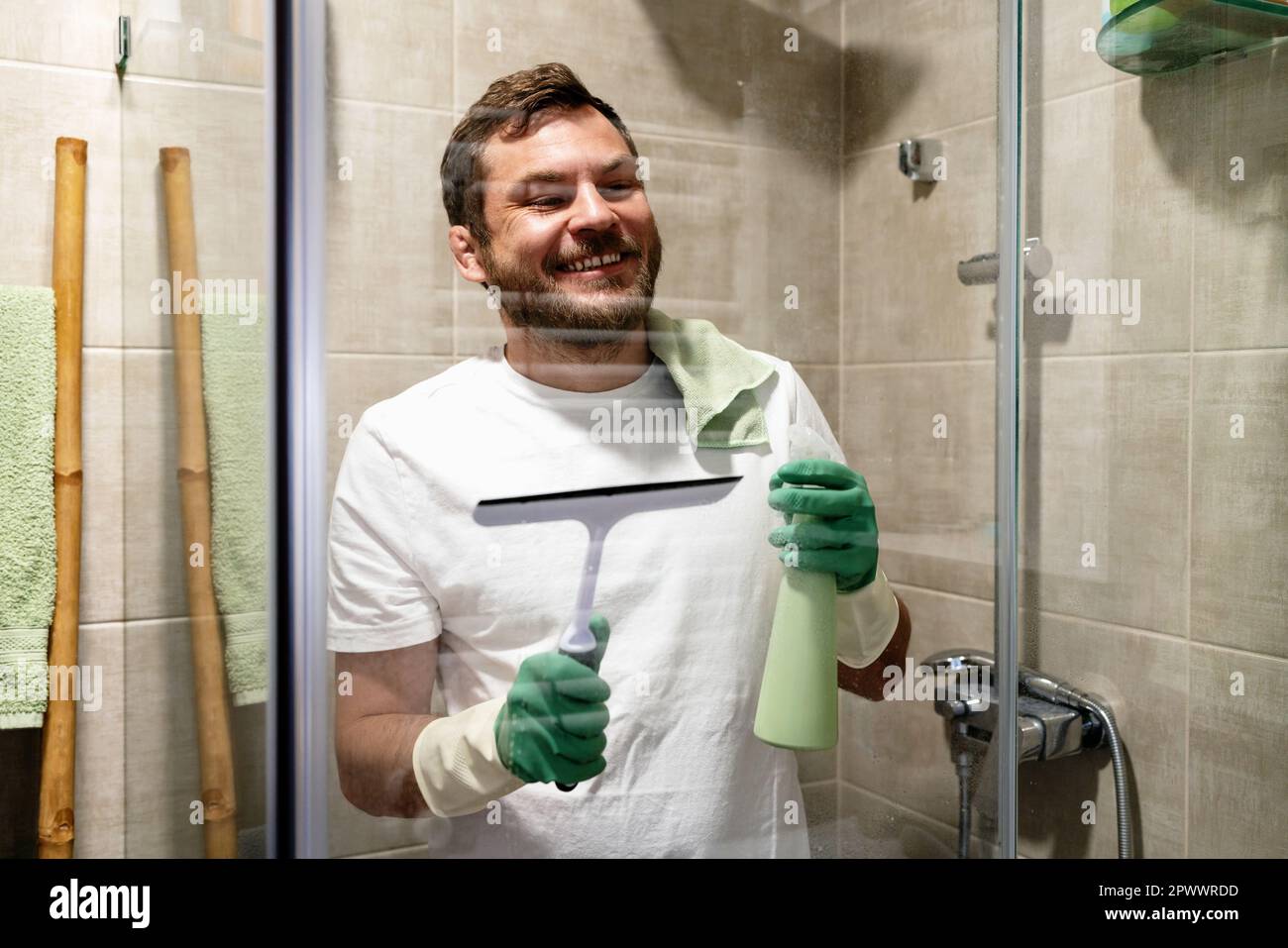 Smiling man cleaning glass wall in shower room Stock Photo - Alamy