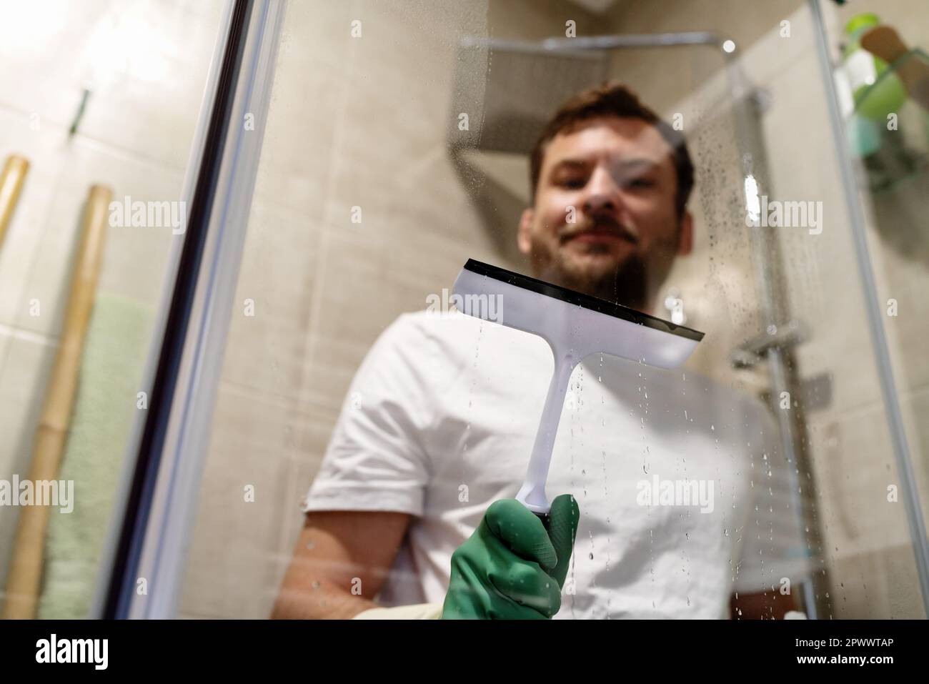 Glass wiper in males hands, cleaning glass wall in bathroom Stock Photo ...