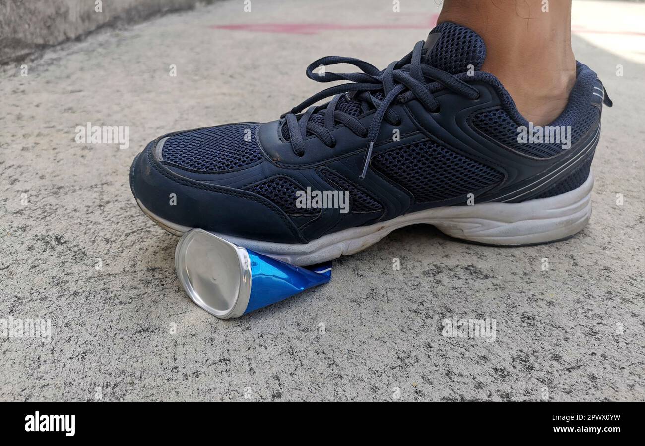 A man stepped stepping compressed cans on cement ground Stock Photo - Alamy