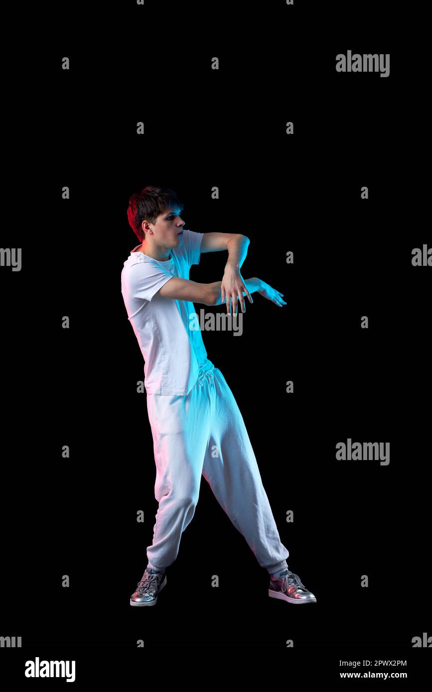 young clubber man in white t-shirt dancing in neon light on black ...