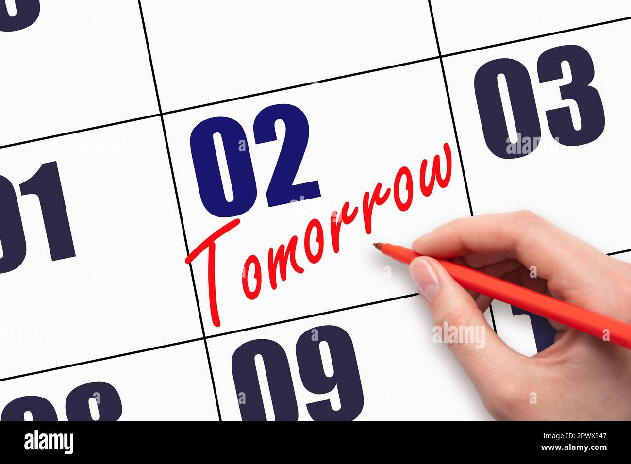 2nd day of the month. Hand writing text TOMORROW on calendar date ...