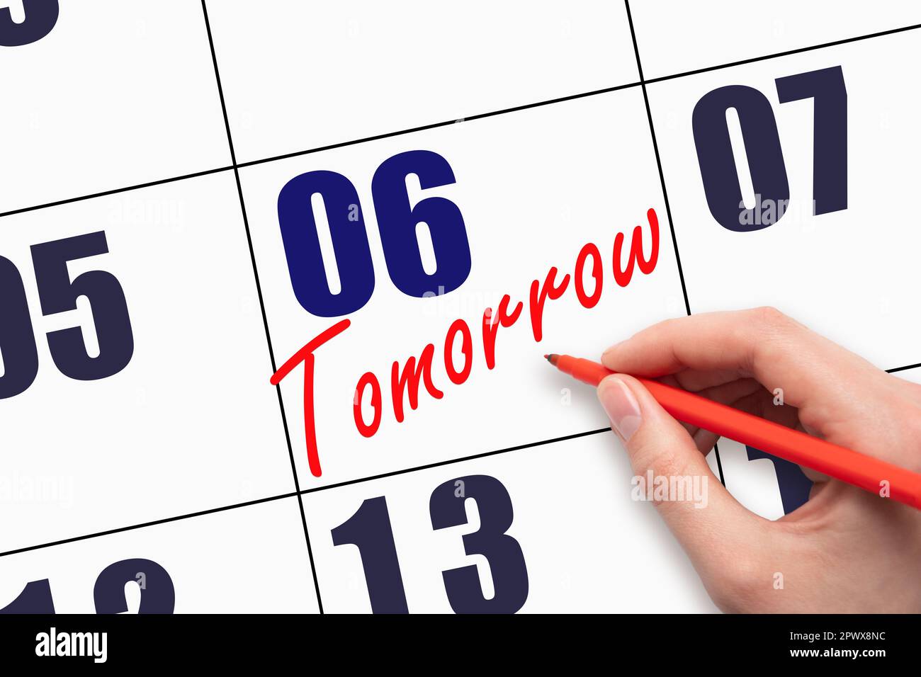 6th day of the month. Hand writing text TOMORROW on calendar date ...