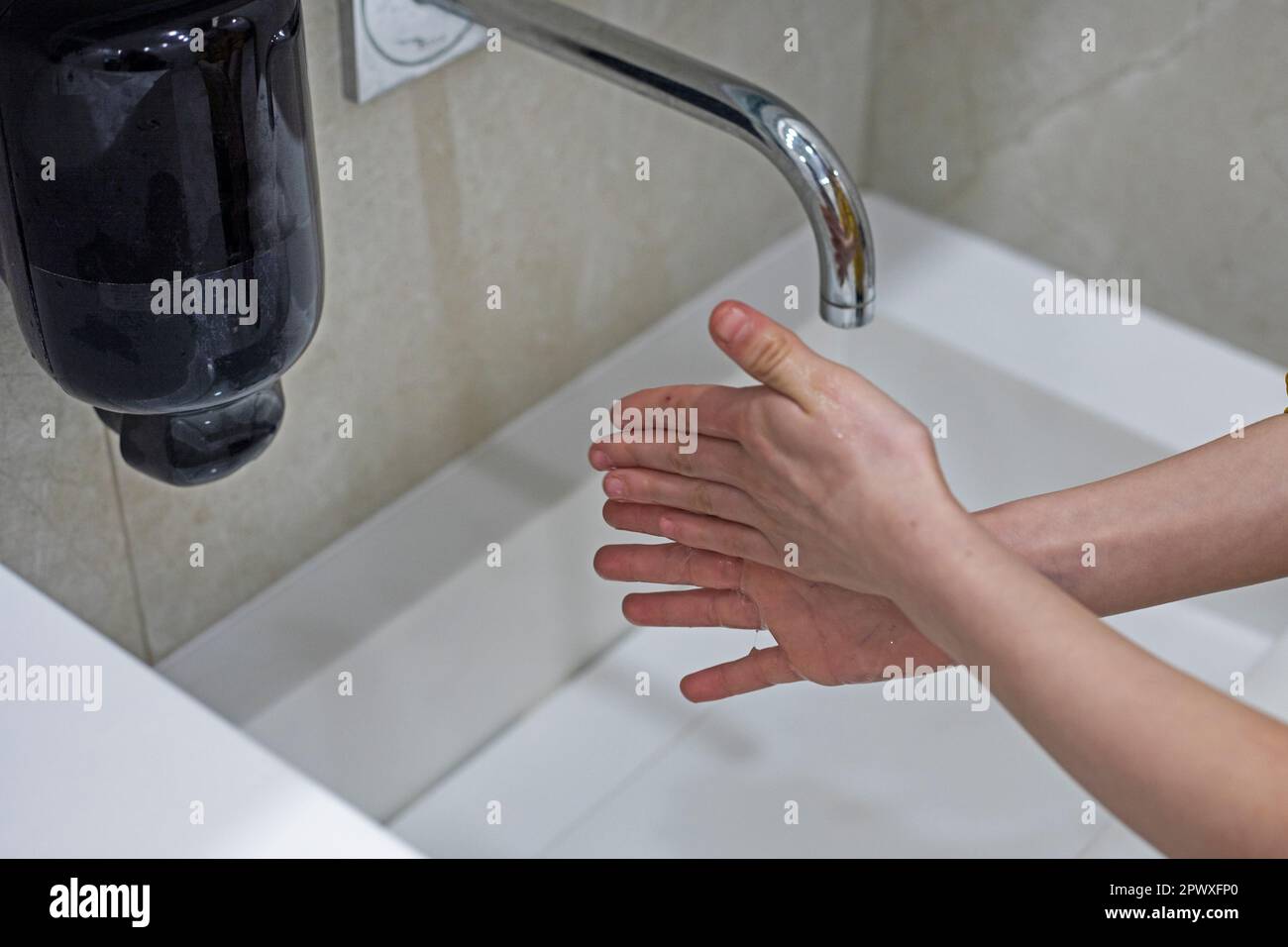 child carefully begins to lather his hands under the tap from ...