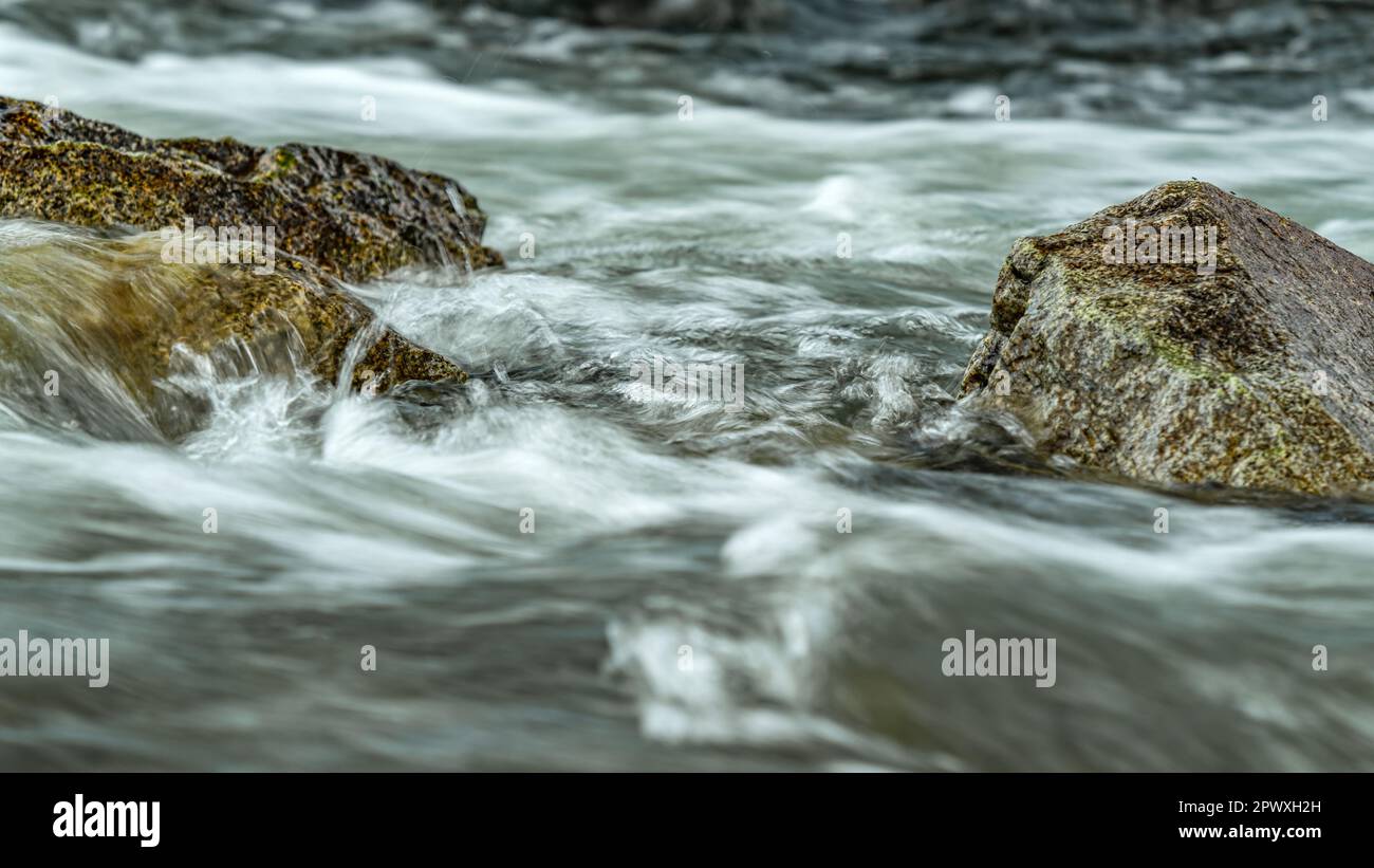 Rapid spring river flowing over rocks forming white water waves ...