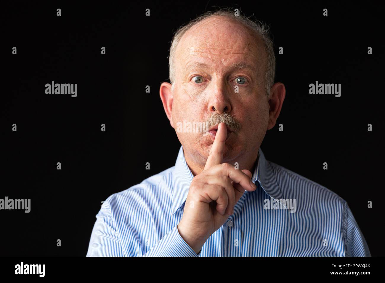 Grey haired senior man with finger on lips for silence or secret ...