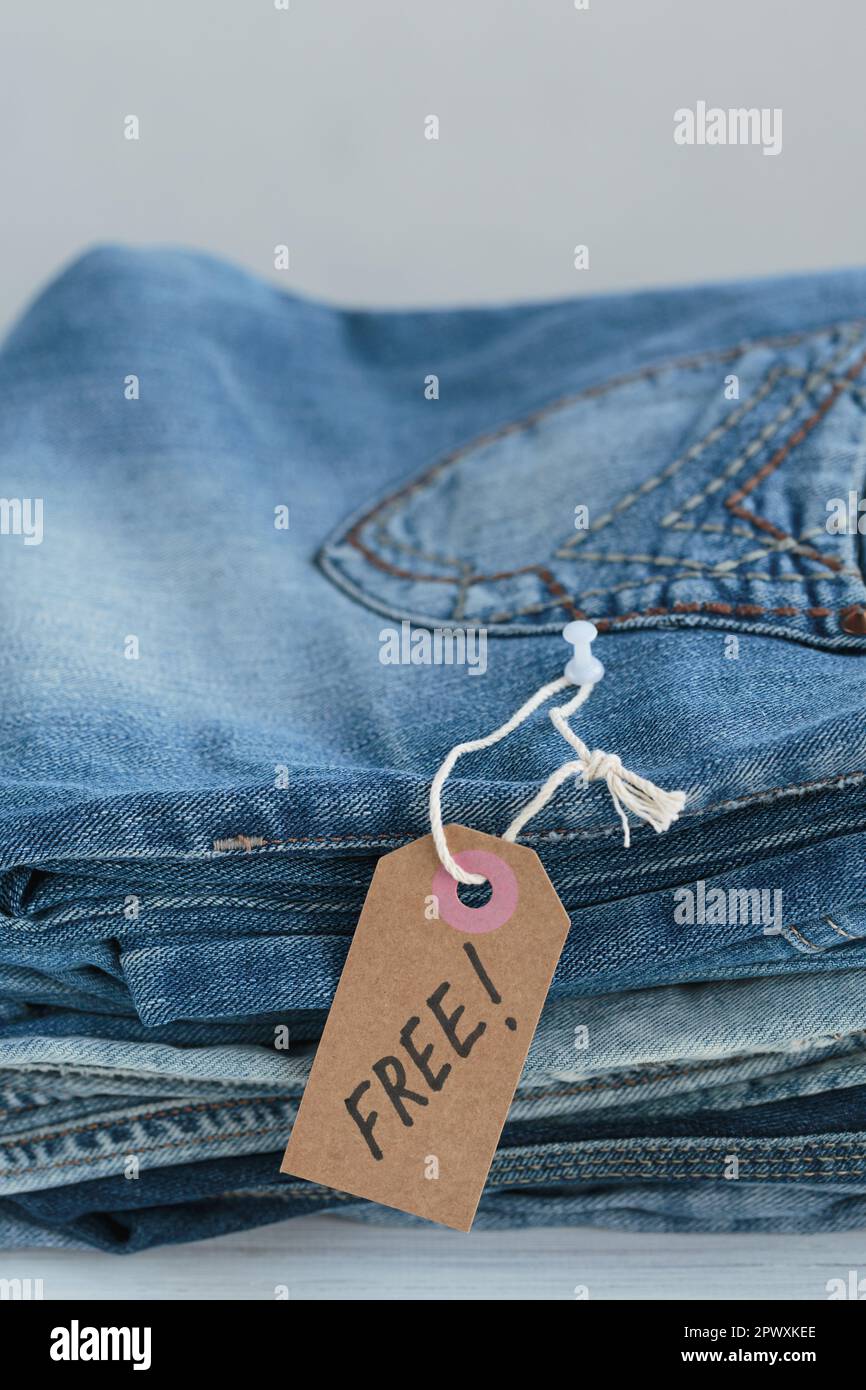 Stack of blue jeans and tag with inscription free on white background ...