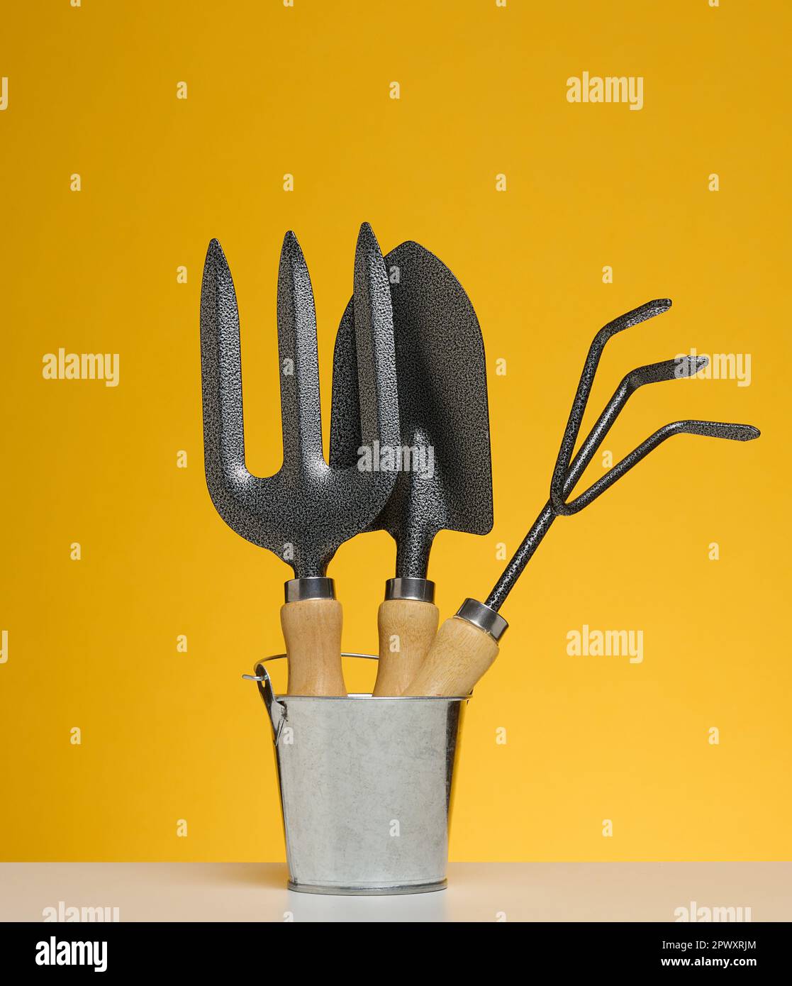 Miniature garden tools in a metal bucket on a yellow background Stock ...