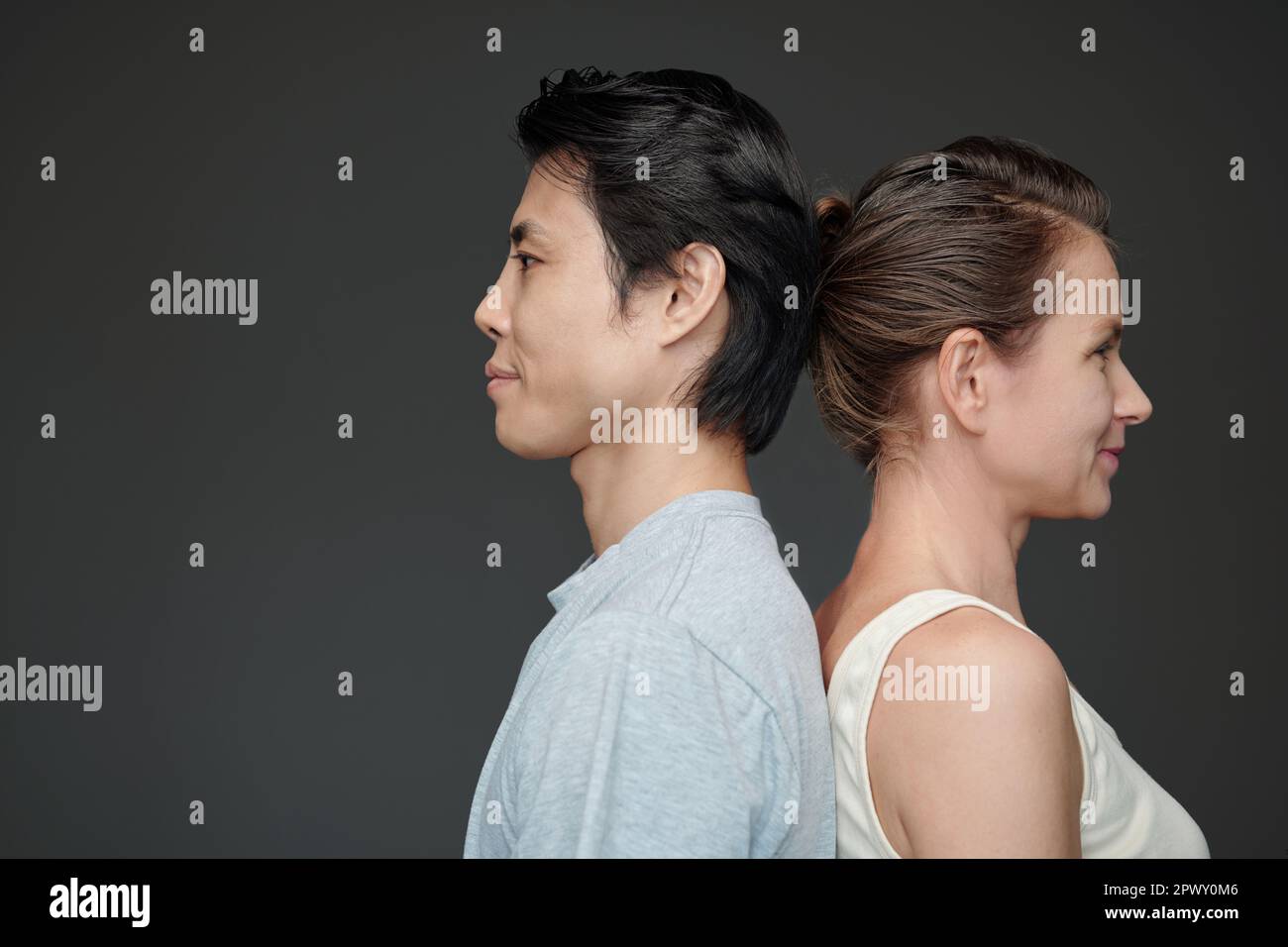 Man and woman standing back to back, isolated on grey Stock Photo - Alamy