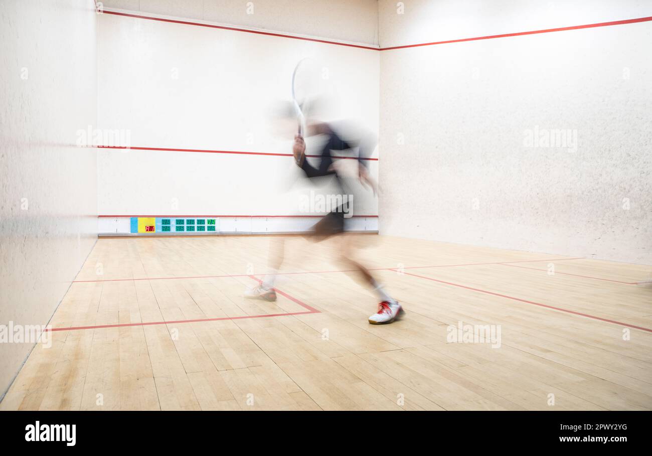 Squash player in action on a squash court (motion blurred image; color ...
