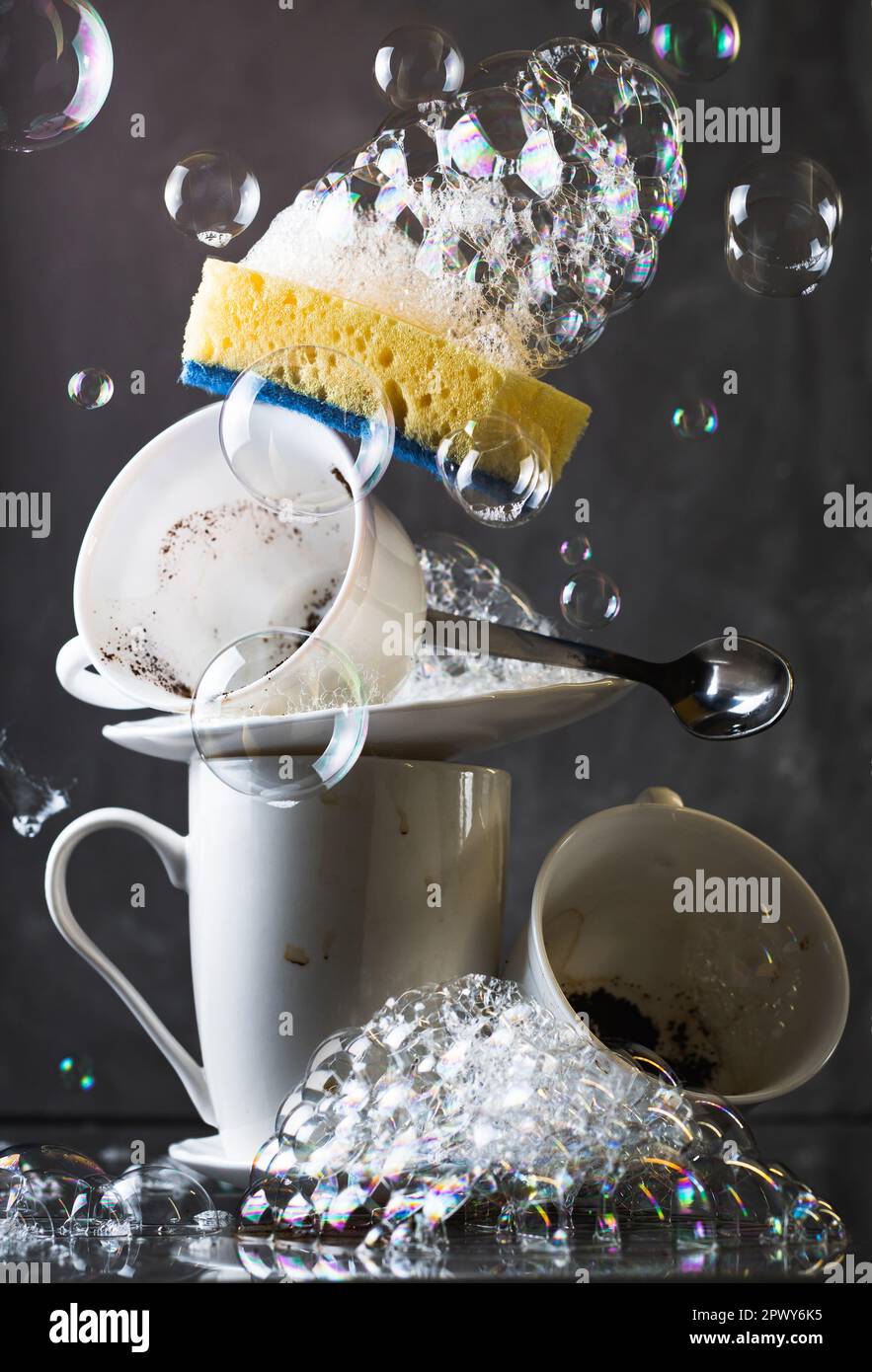 Stack of dirty white dishes on dark background, with washing sponge and ...