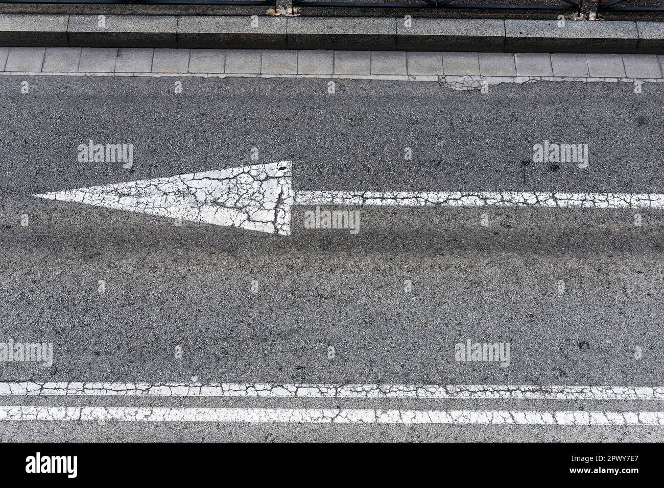 Overview of an arrow and traffic dividing lines on cracked asphalt ...