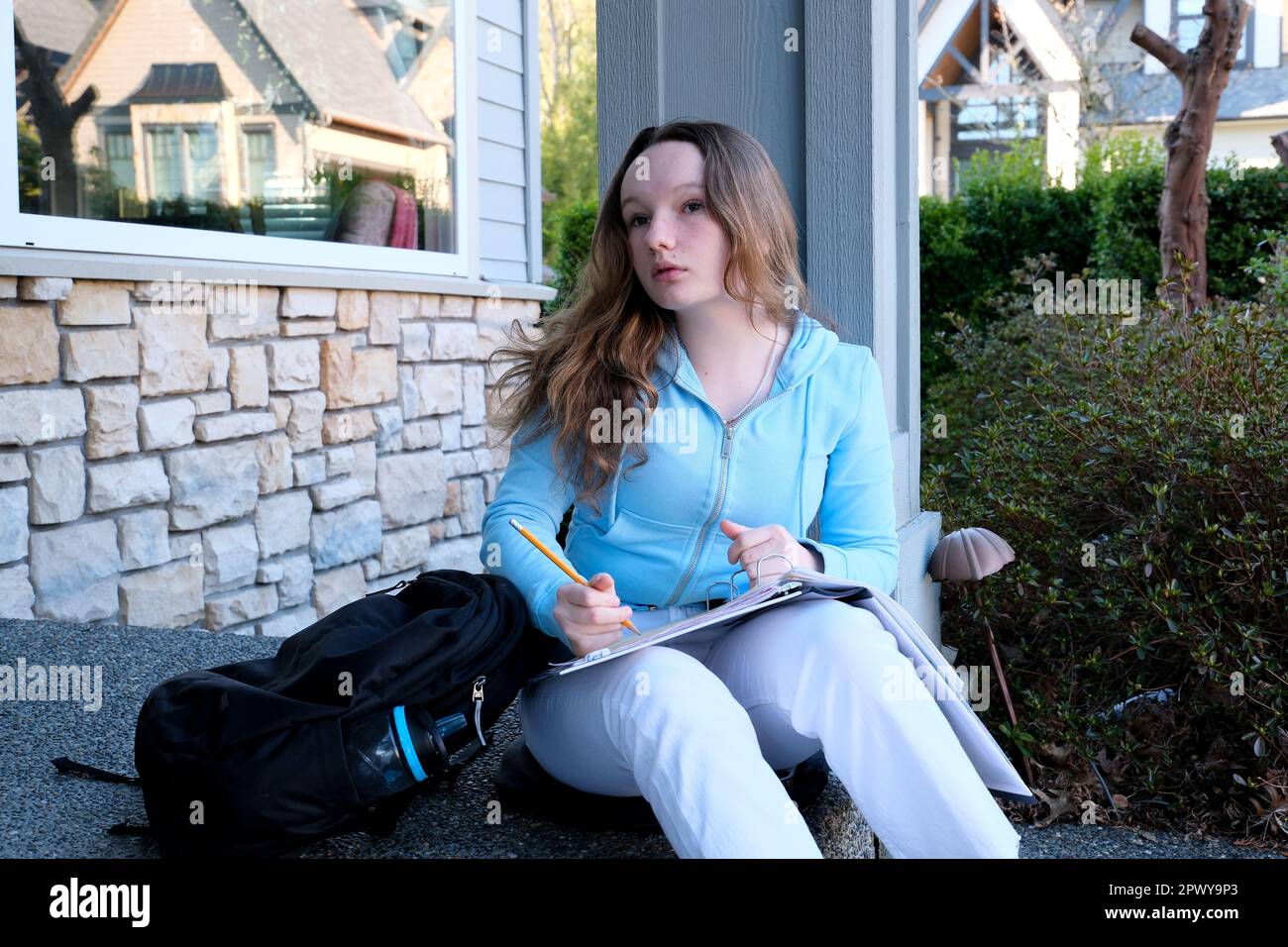 Side view of cute teen girl in red cap is sitting outside and drawing ...
