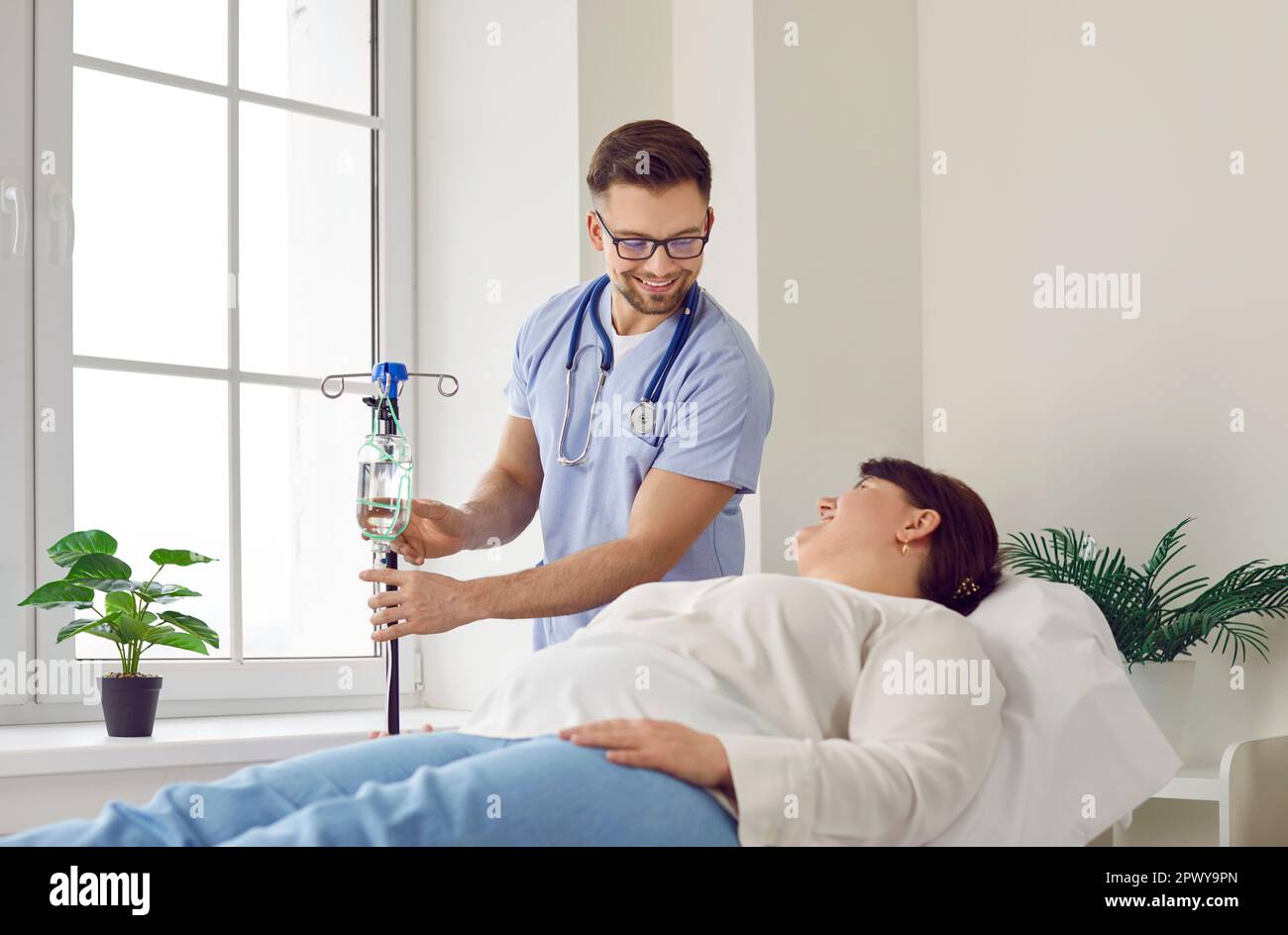 Nurse gives an IV line to a woman patient lying on the medical bed at the hospital Stock Photo ...