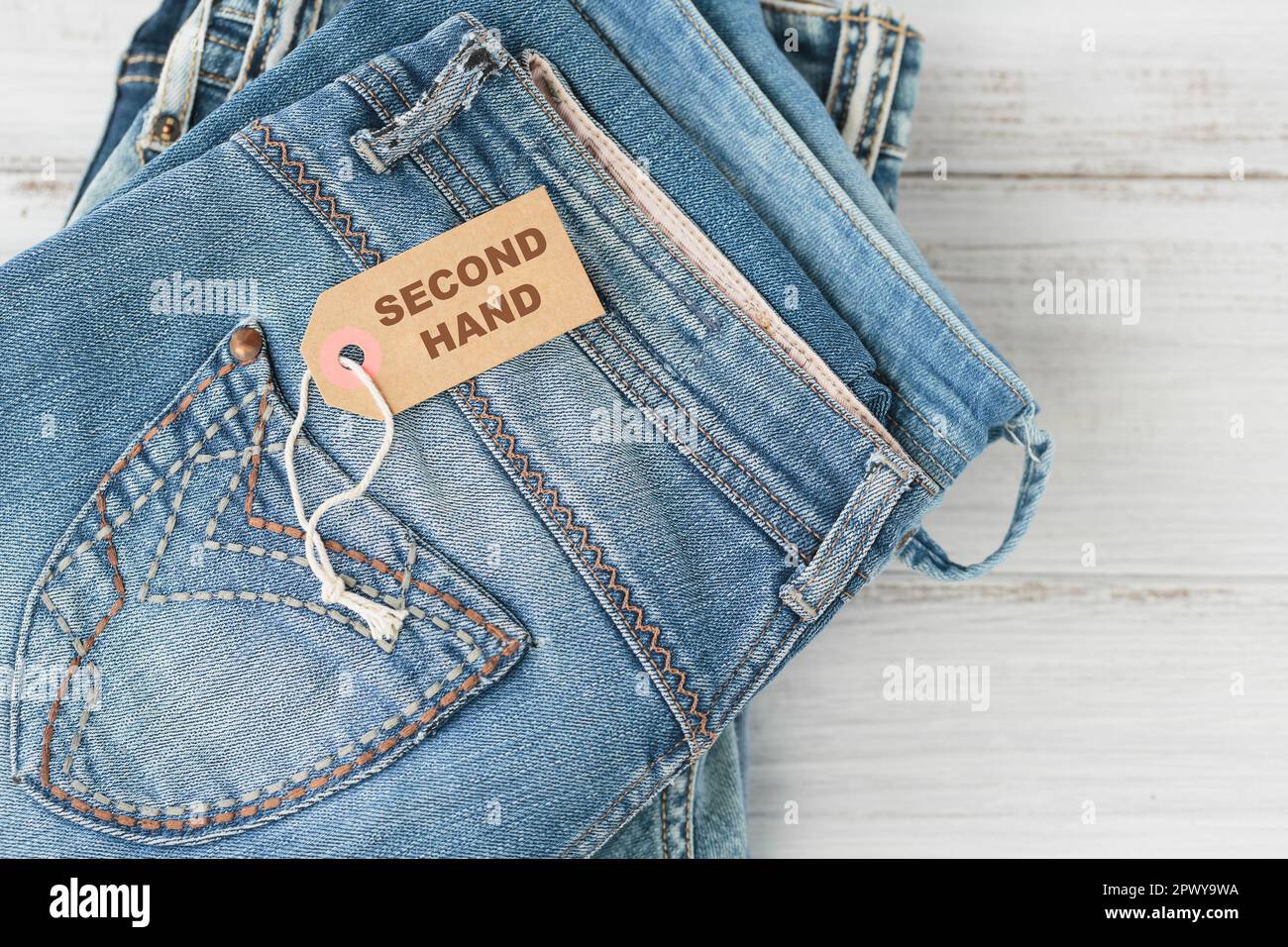 Stack of blue jeans and tag with inscription second hand on white ...